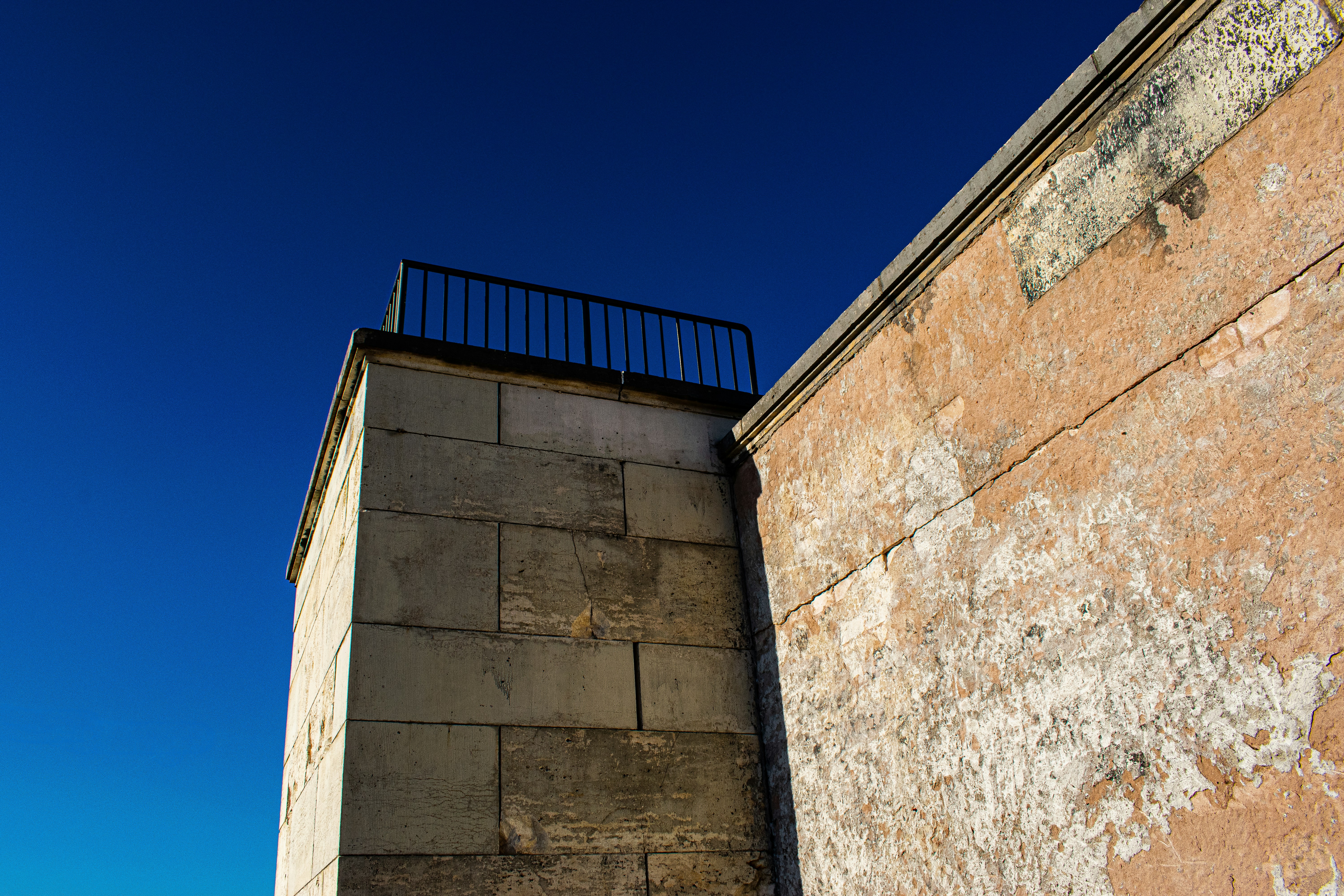 Stone wall of a historic structure against a deep blue sky.