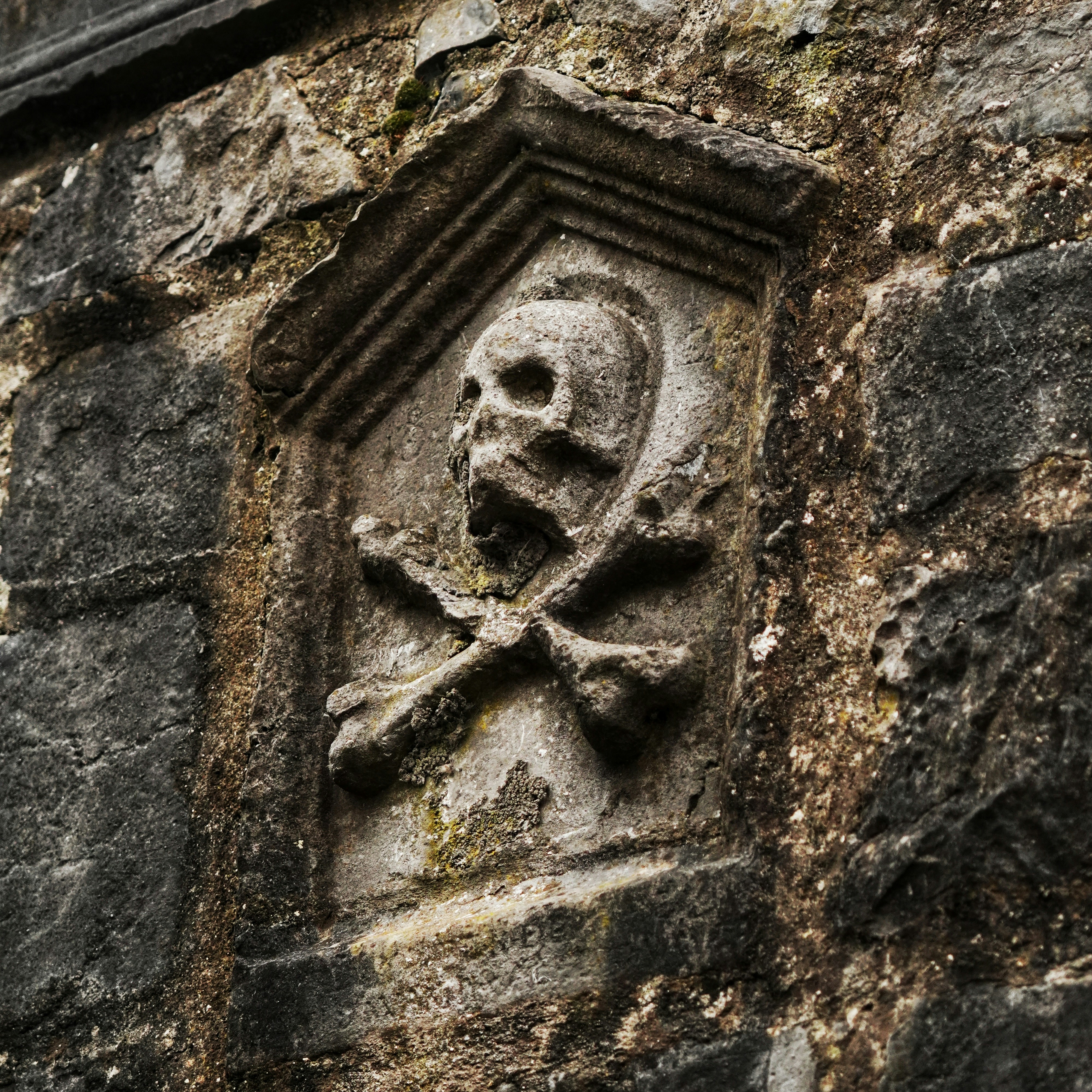 A skull and crossbones carved into a stone wall photo – Free Face Image ...
