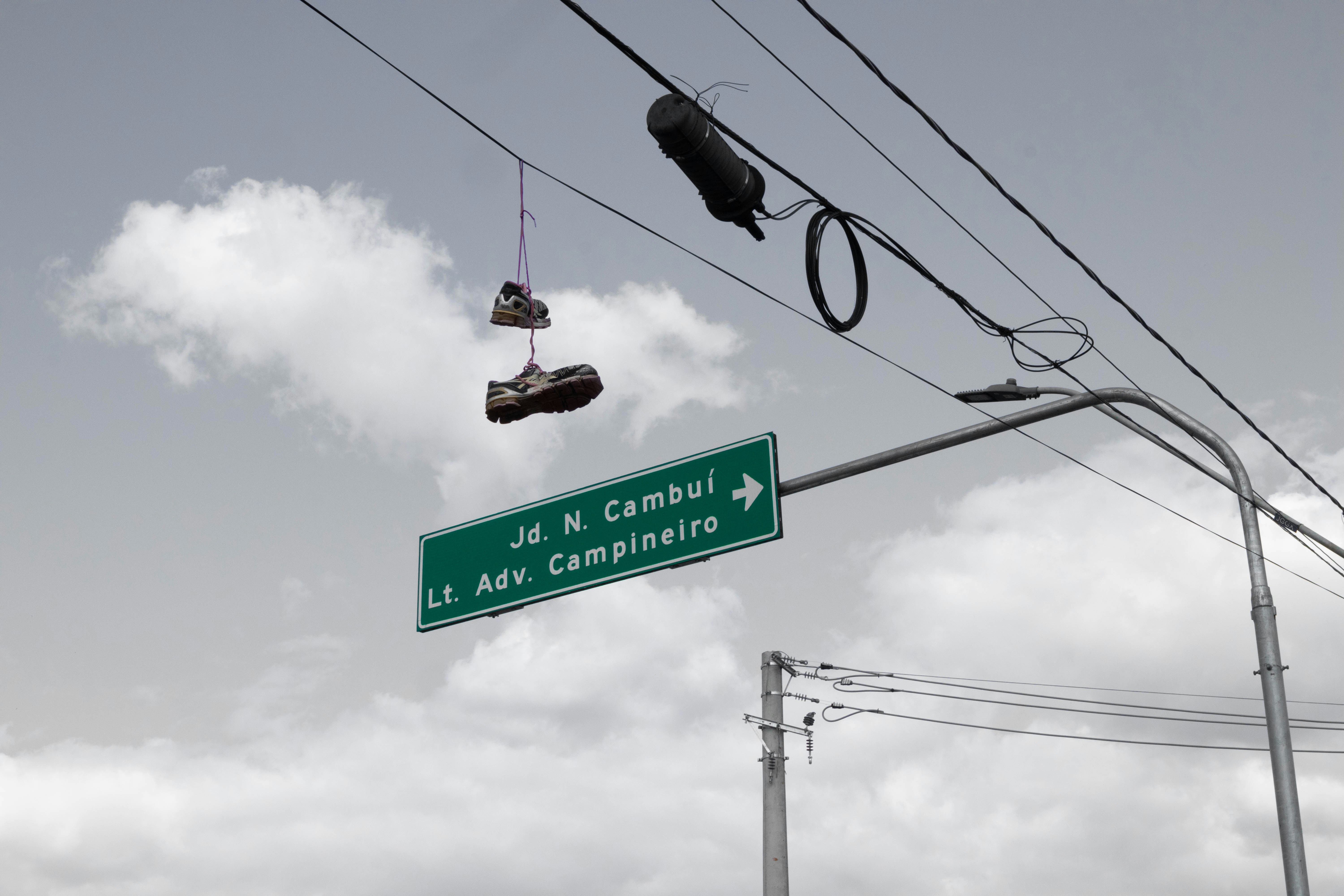 Hanging Shoes and Green Road Sign: City Junction under Cables