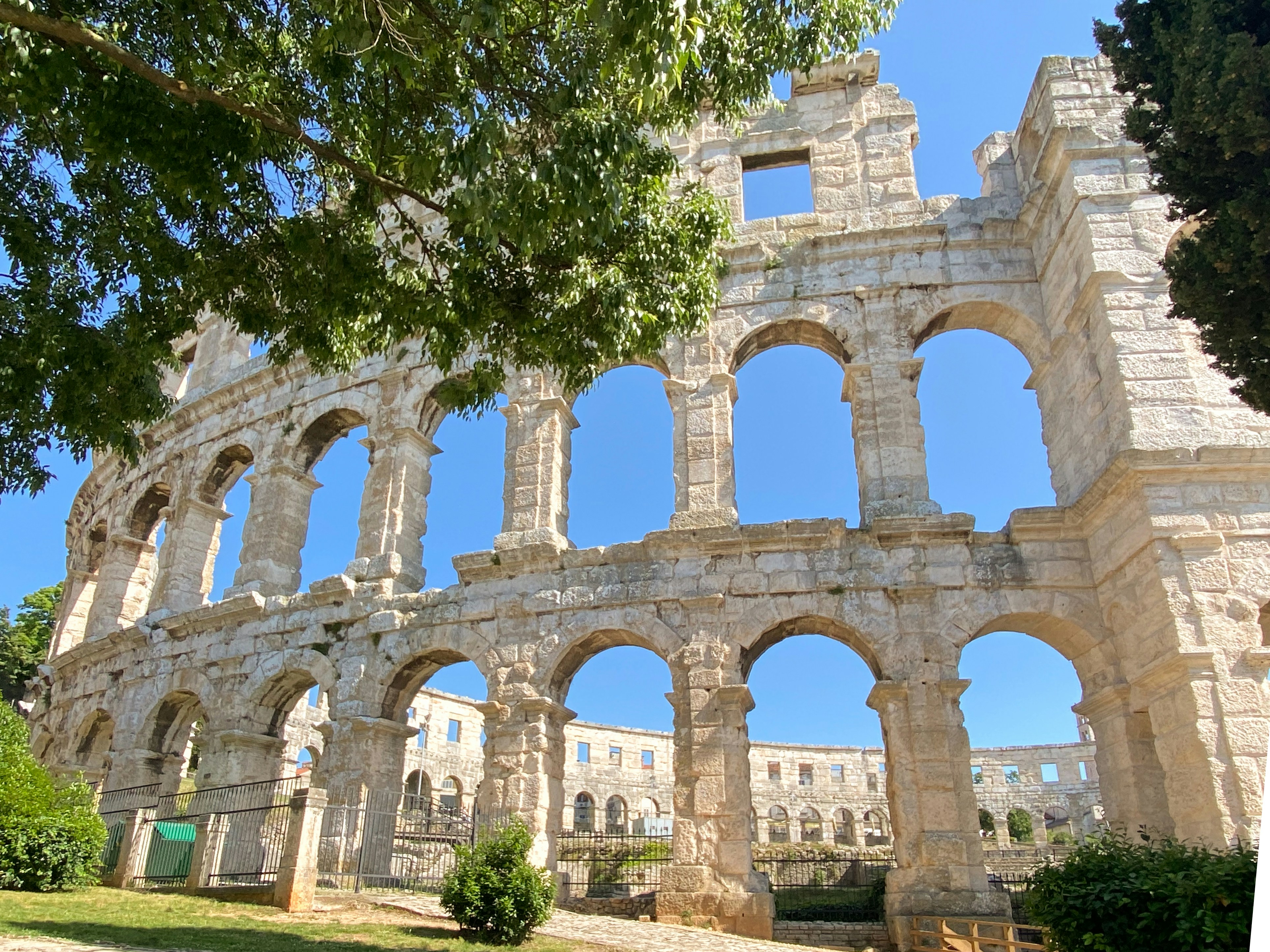 The Pula Amphitheater | a large stone structure sitting under a tree