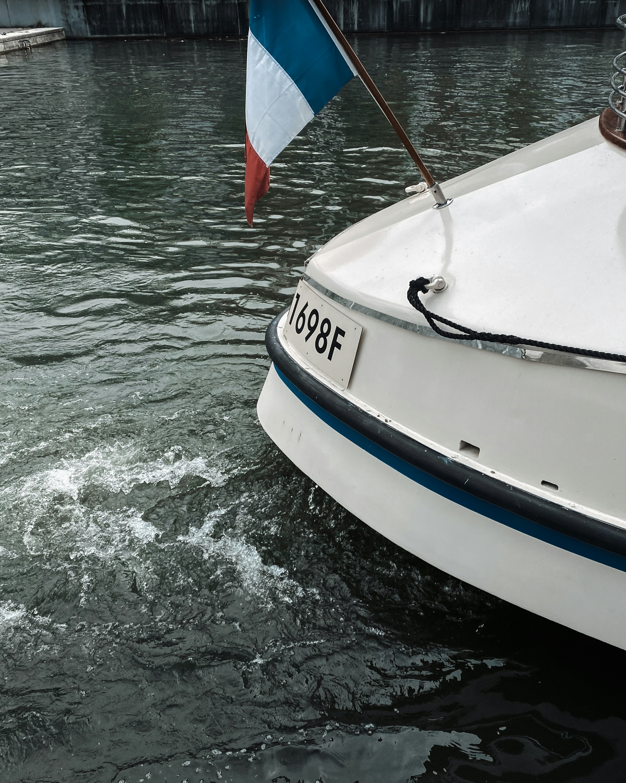 Rear Portrait of a White Motorboat at a Quiet Marina, Flag Aloft