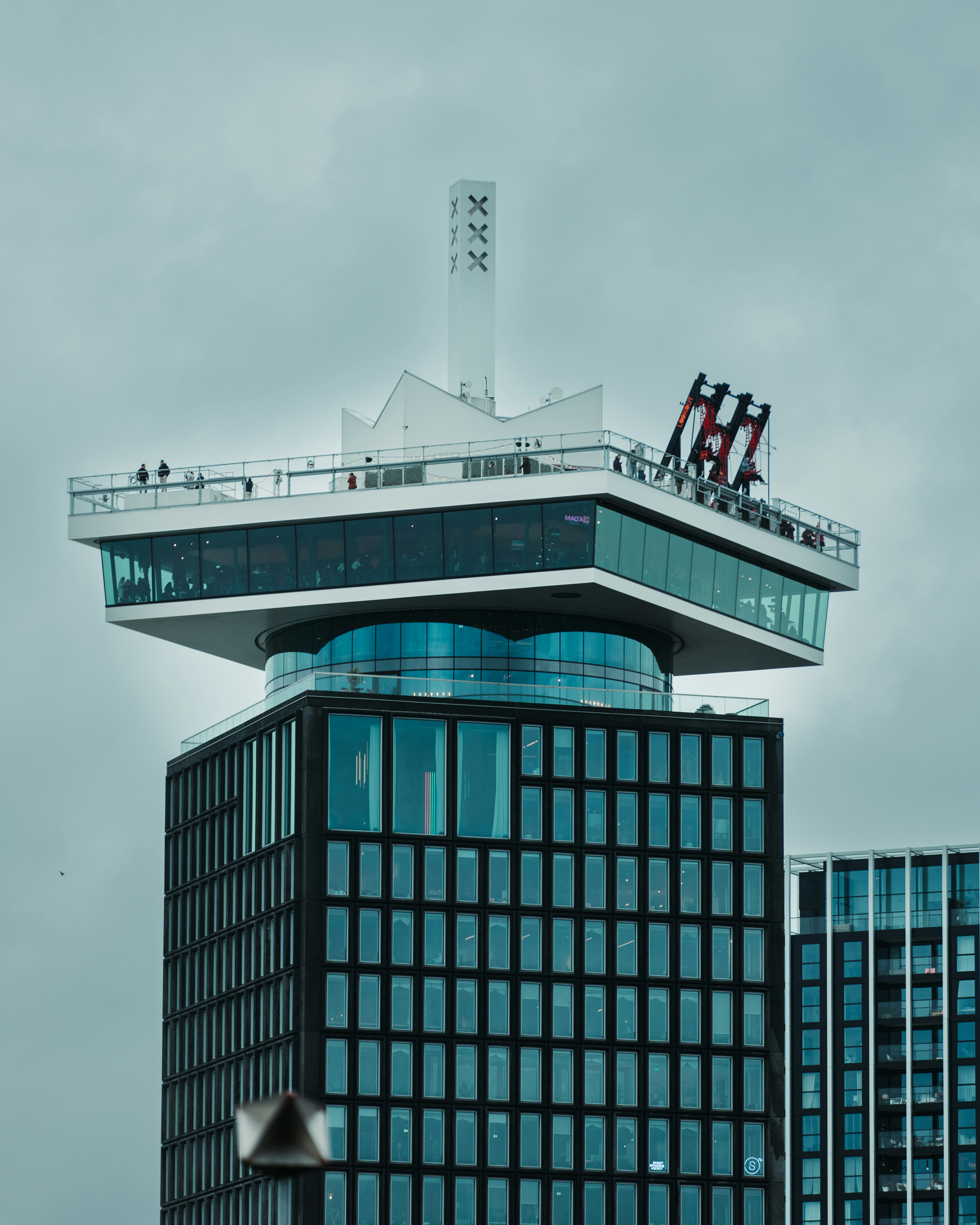 The A'DAM Tower with its distinctive rooftop swings against a cloudy sky.