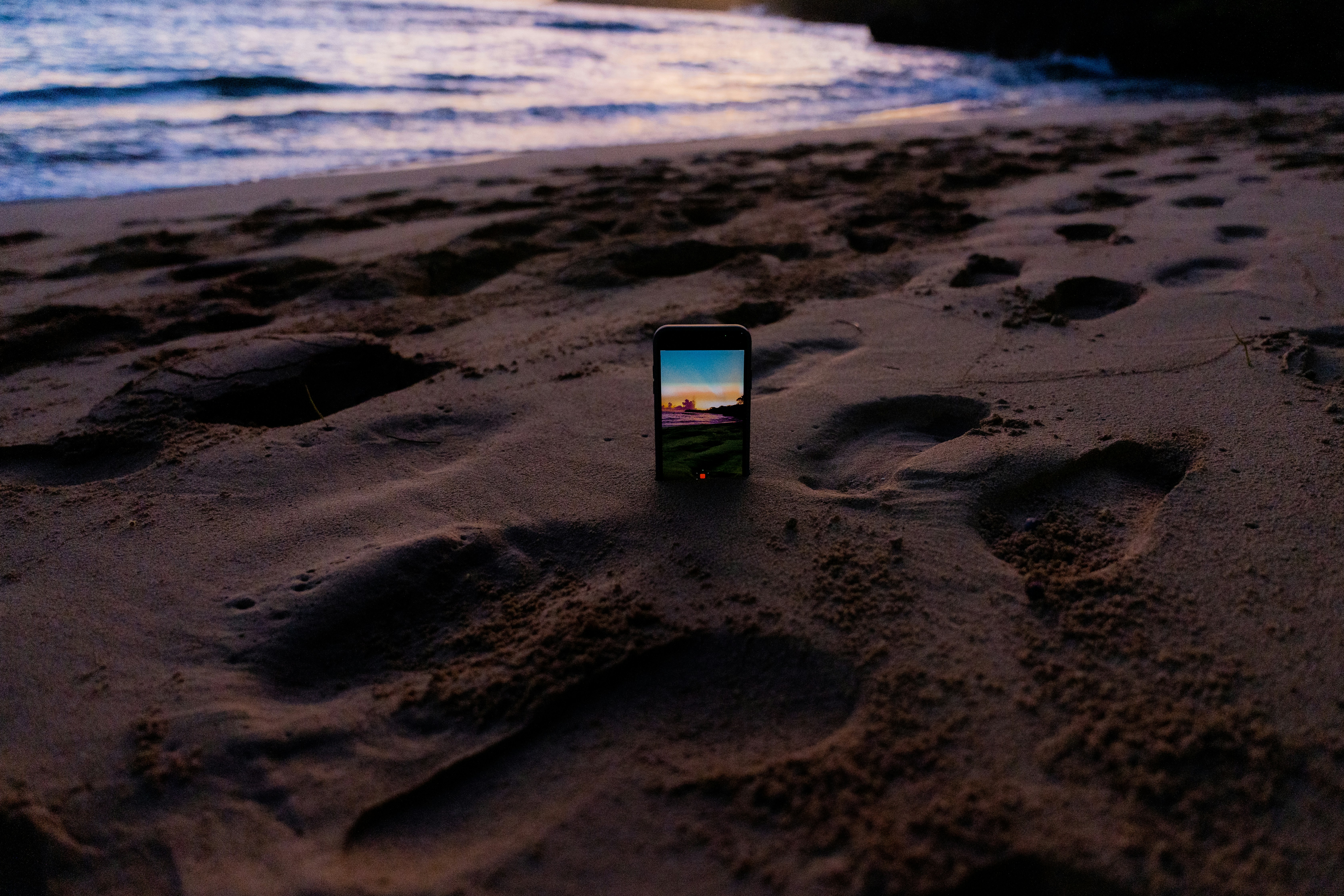Phone in a Crest of Sand: Sunset Reflections on a Quiet Beach