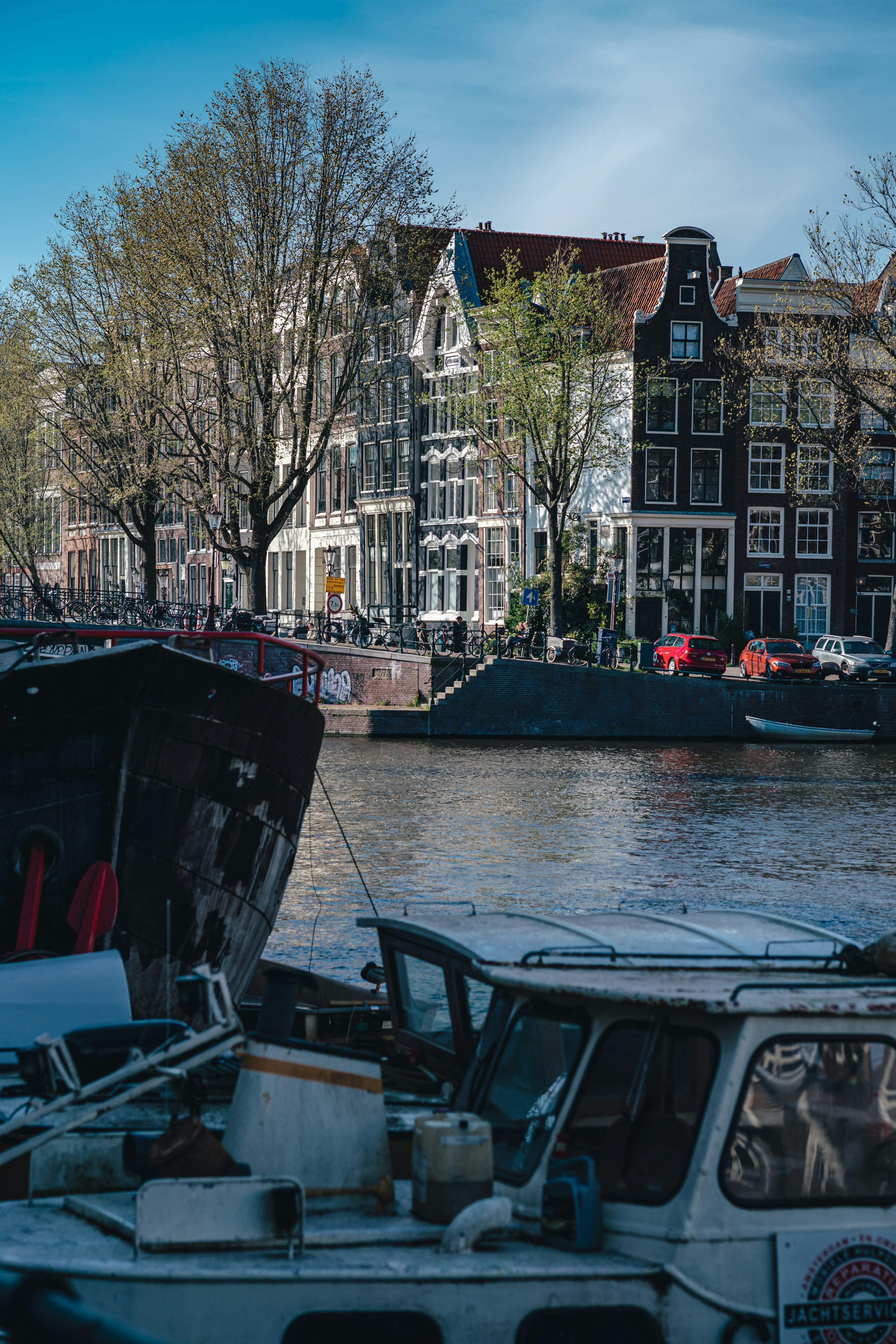 A picturesque view of the canals in Amsterdam. The shimmering water, historic buildings, and the gentle sway of boats create a timeless tableau of the city's charm and character.