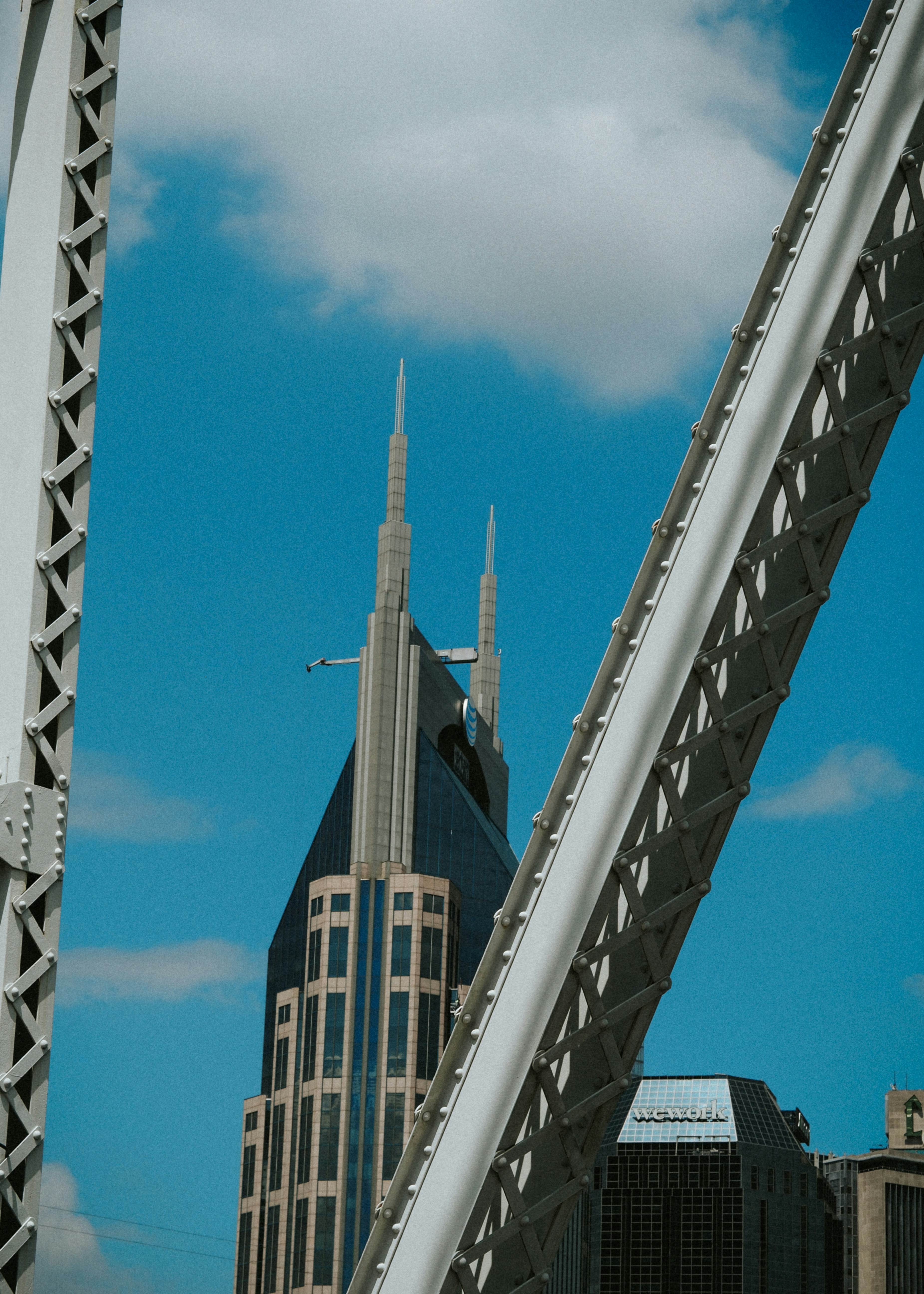 Spire Through Steel: City Skyline Framed by Bridge Girders