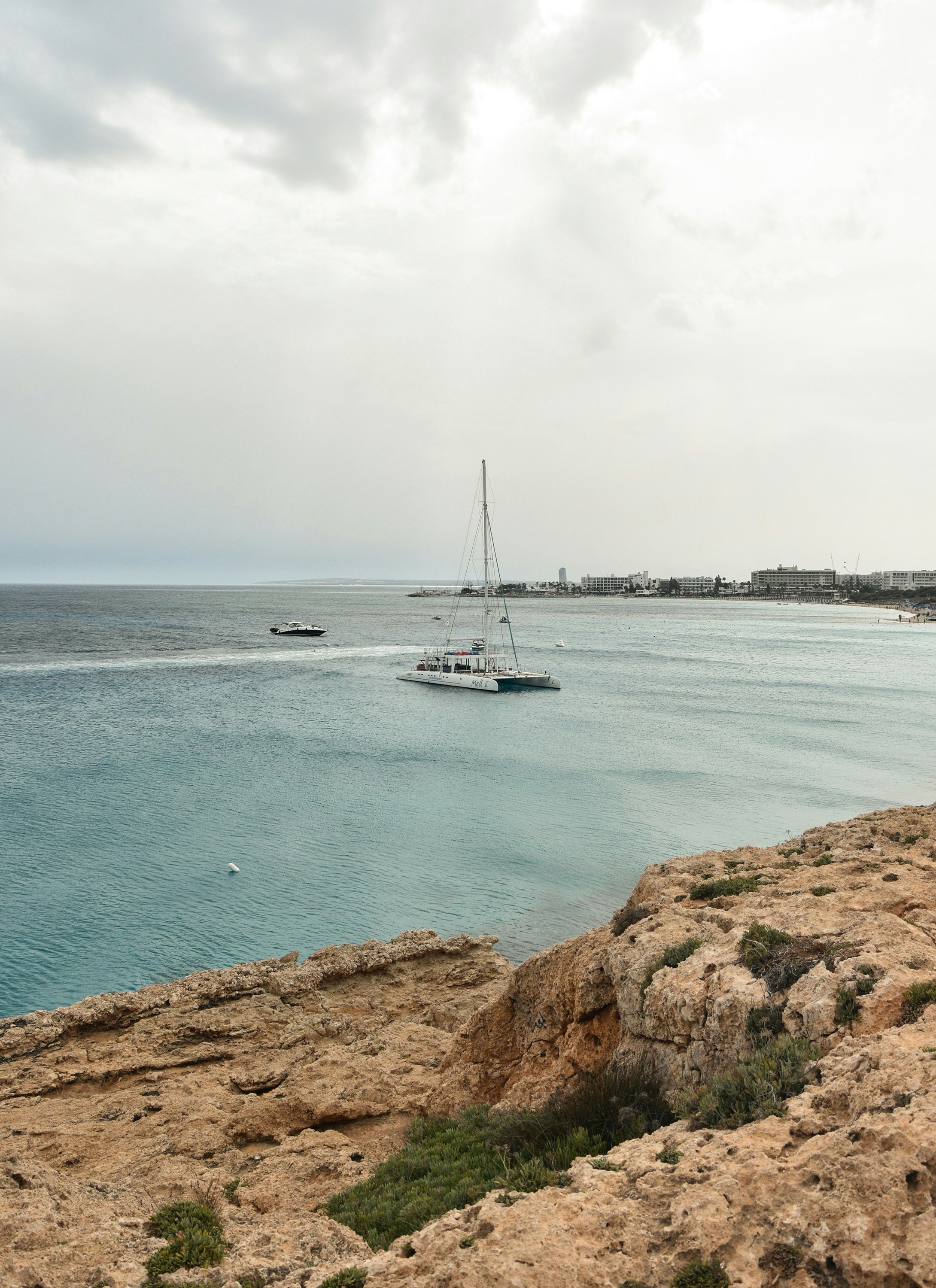 Mast in the Mist: A Catamaran Anchored on a Turquoise Coast