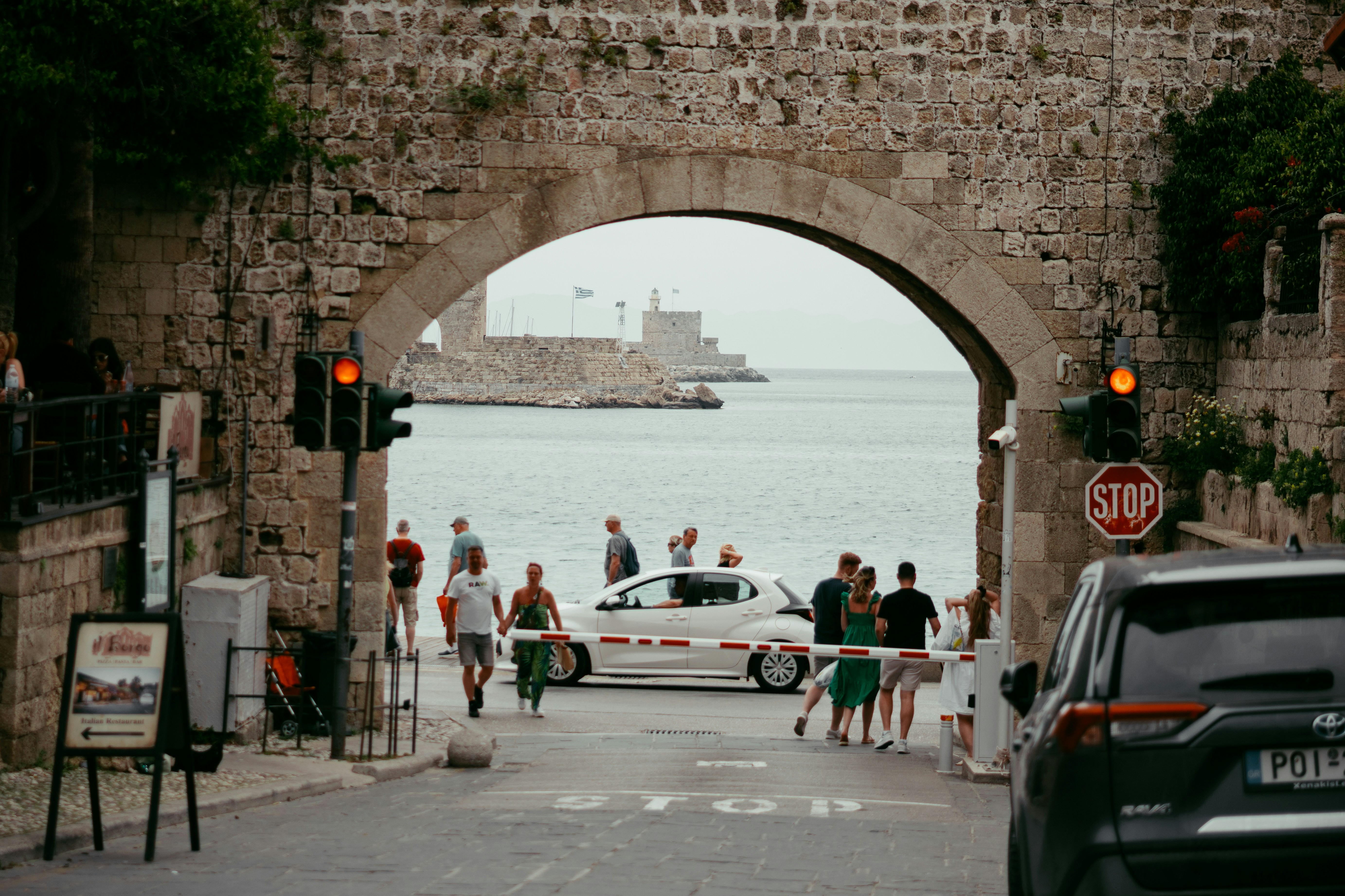 Harbor Arch: Pedestrians Pause at the Stone Gate with Sea Beyond