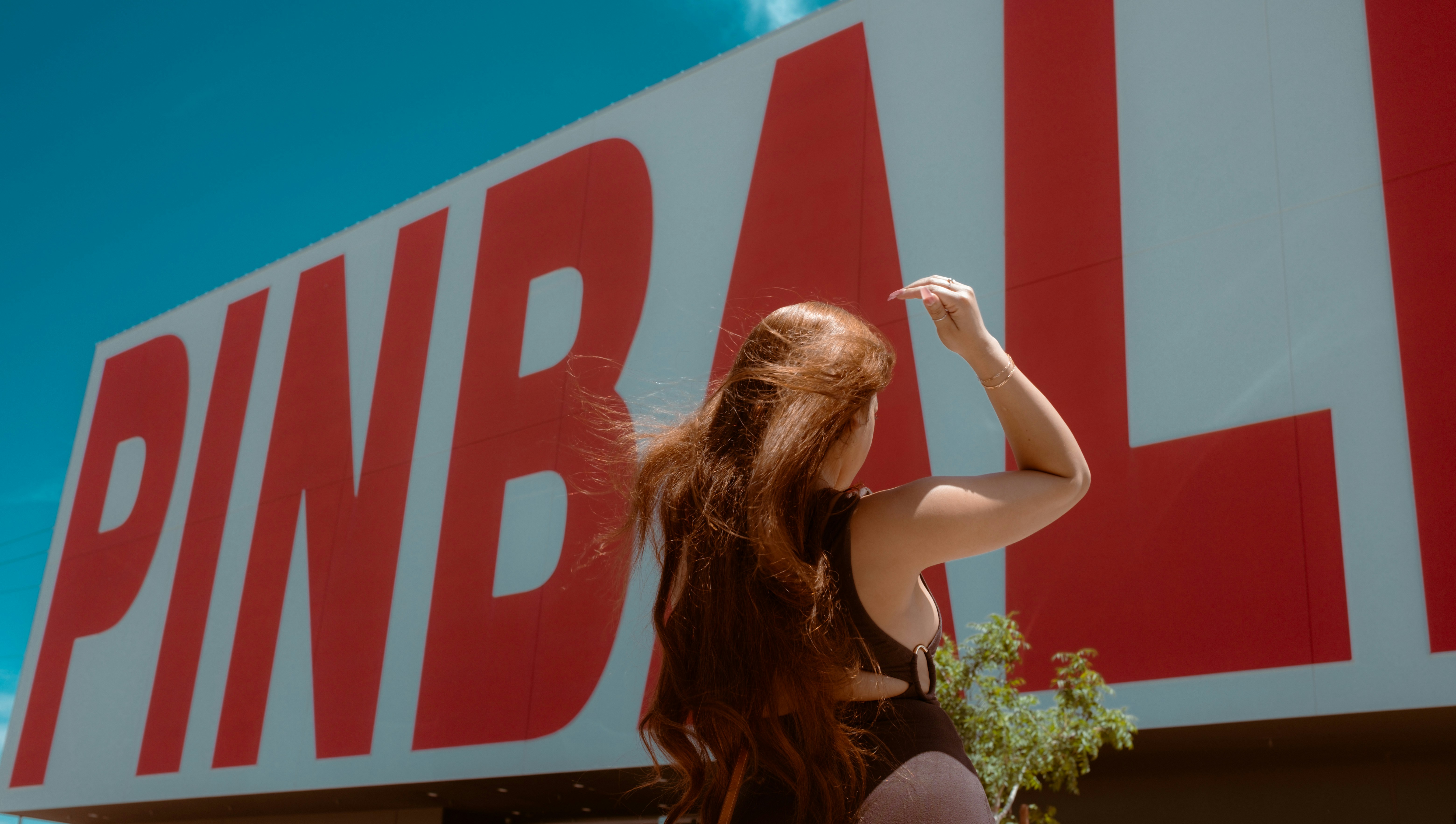 A woman standing in front of a pinball sign photo – Free Woman Image on ...