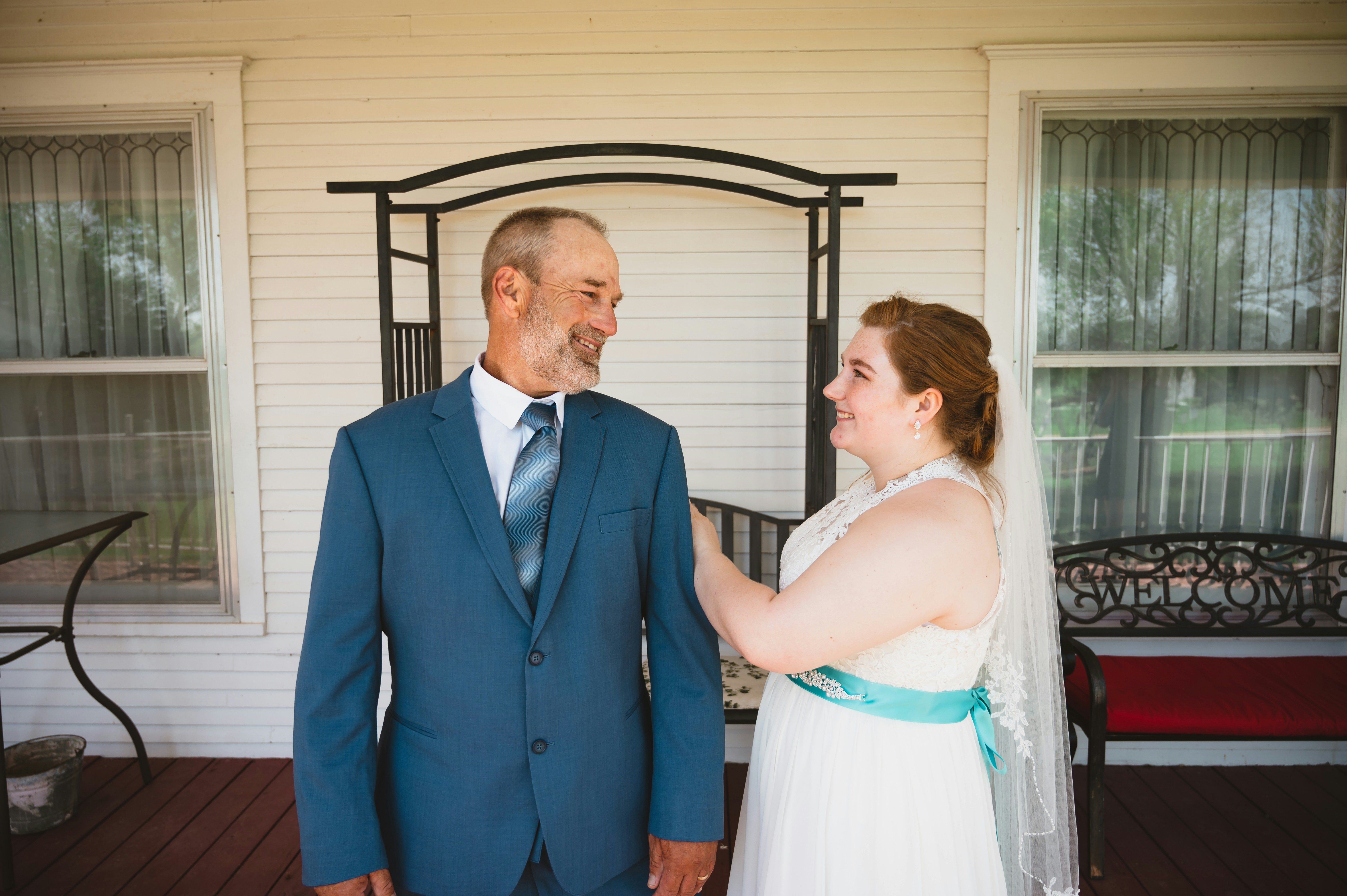 Teal-Sash Moment on the Porch: A Bride and Groom Share a Quiet Wedding Portrait