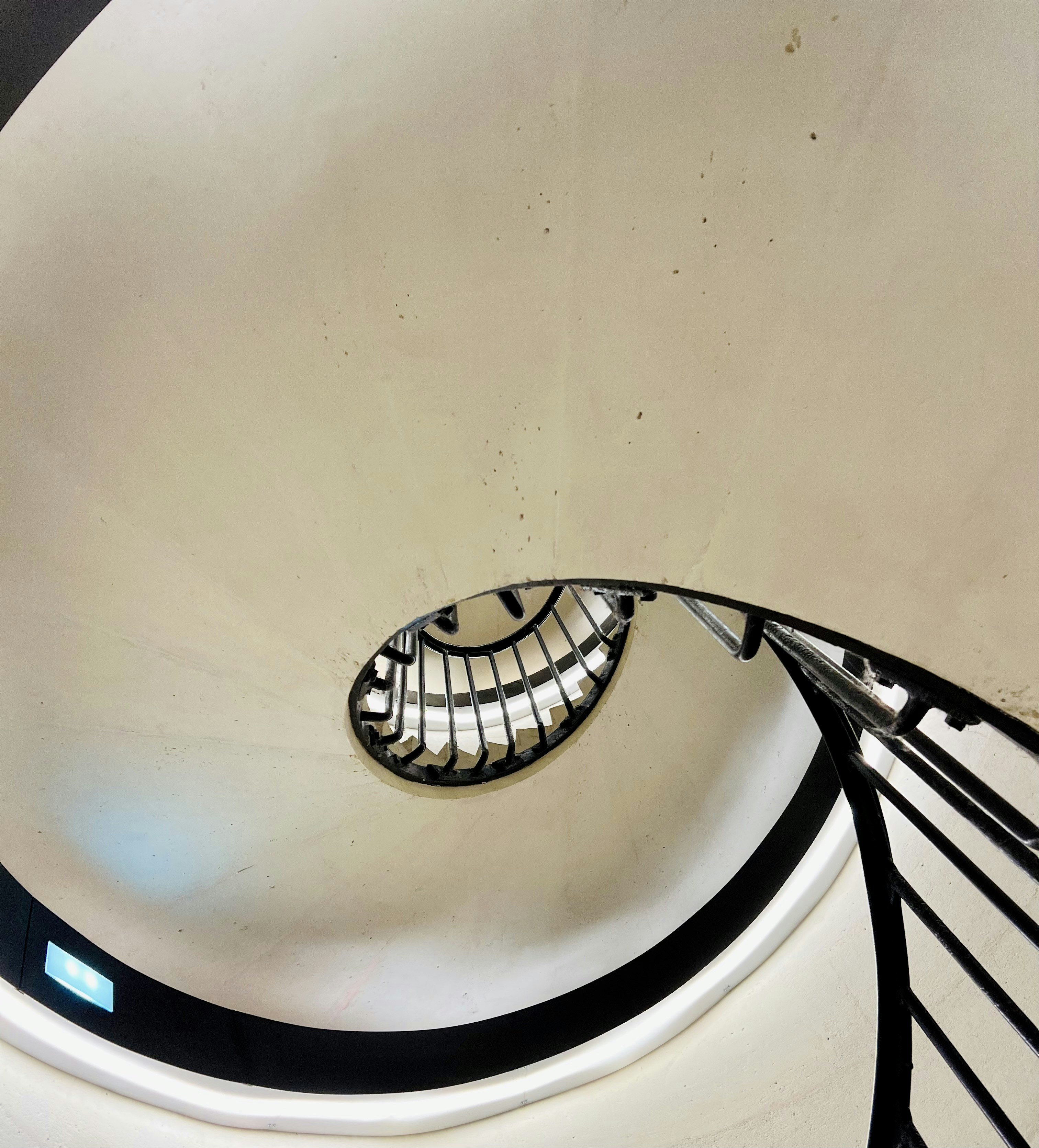 Spiral Descent: White Walls and Black Rails in a Circular Stairwell