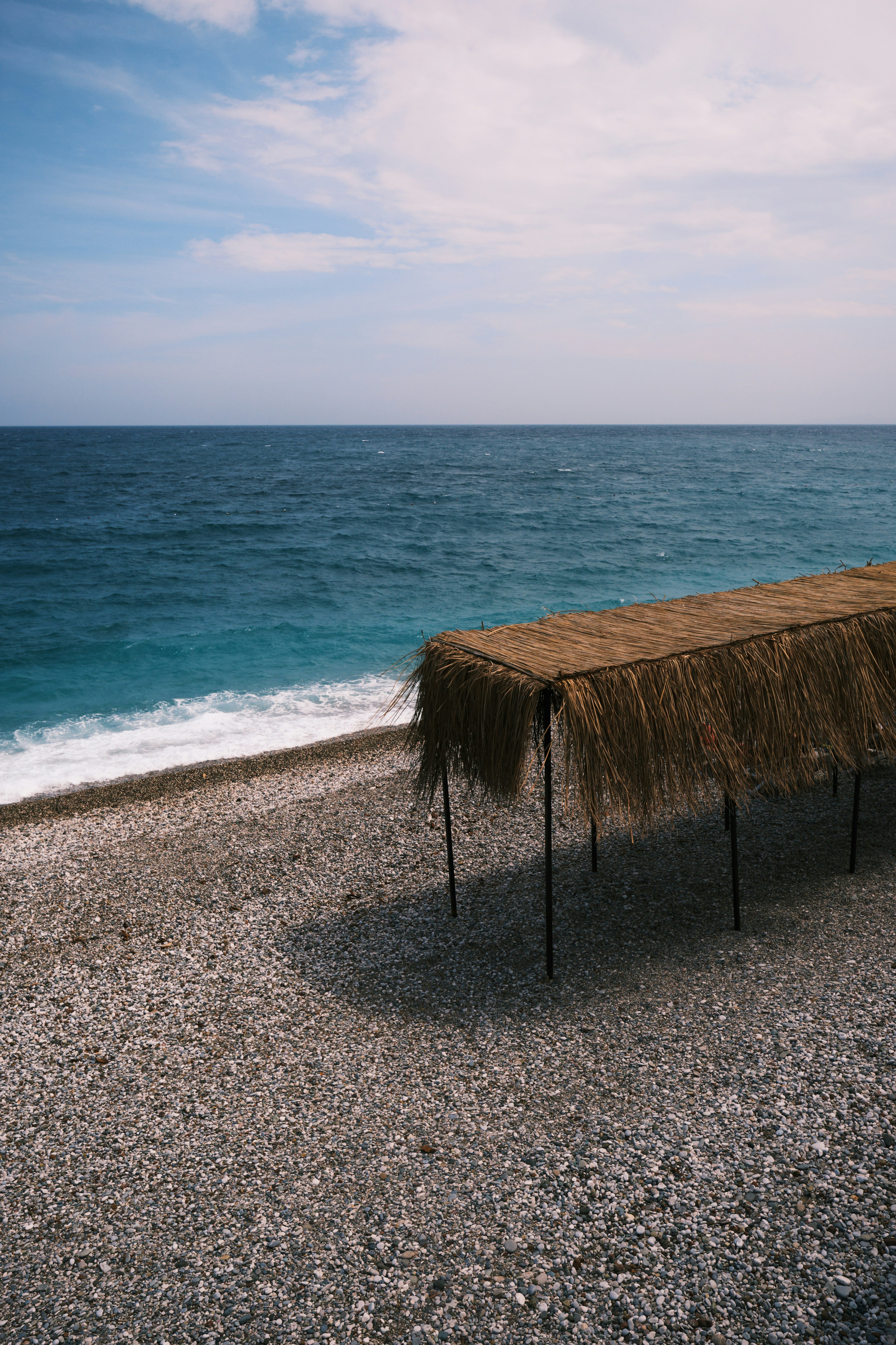 Thatched Shelter on a Pebble Beach: Quiet Blue Horizons