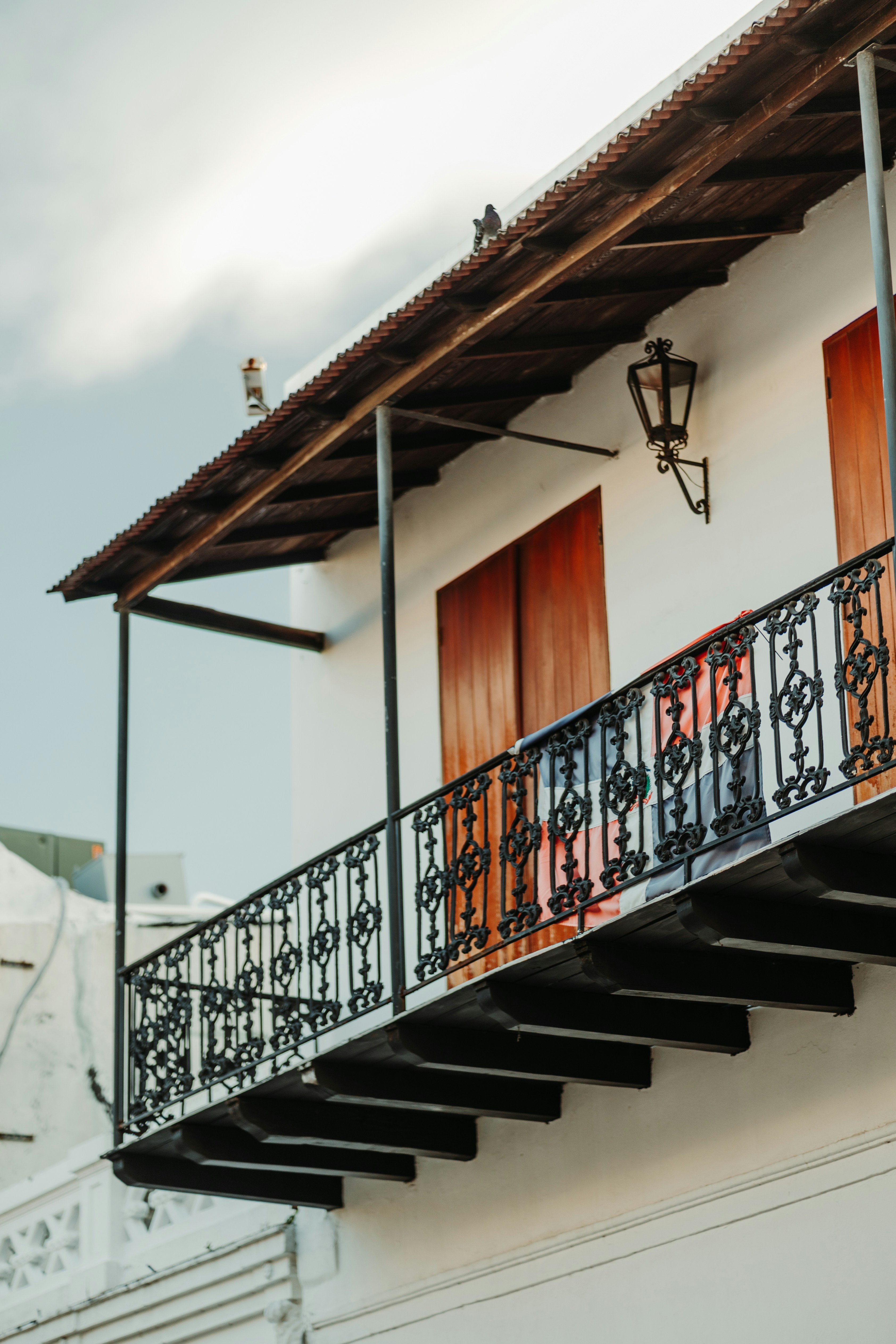 Un balcón con barandilla de hierro forjado y puertas rojas foto – Imagen de Zona colonial ...