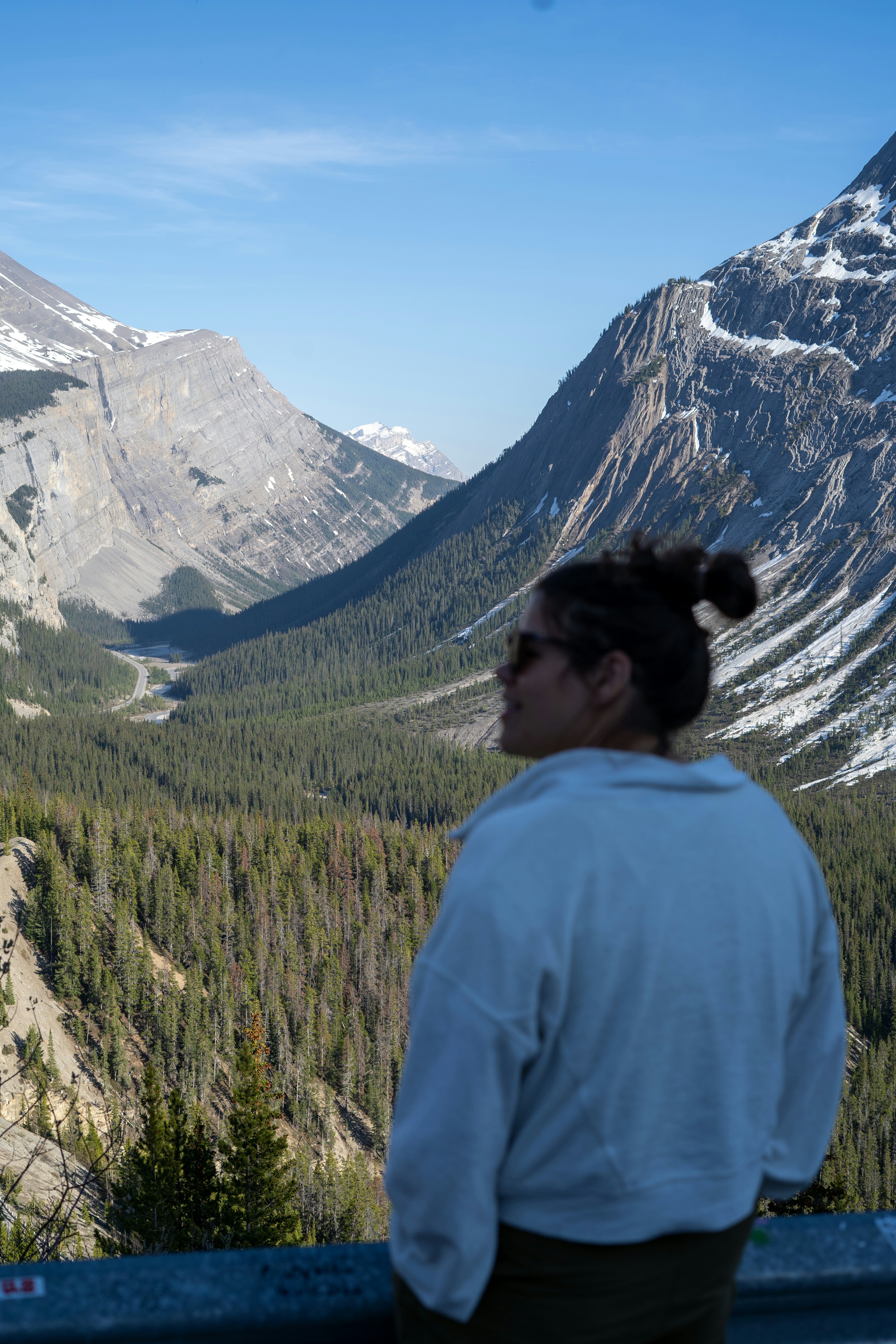 A woman looking out over a valley with mountains in the background ...