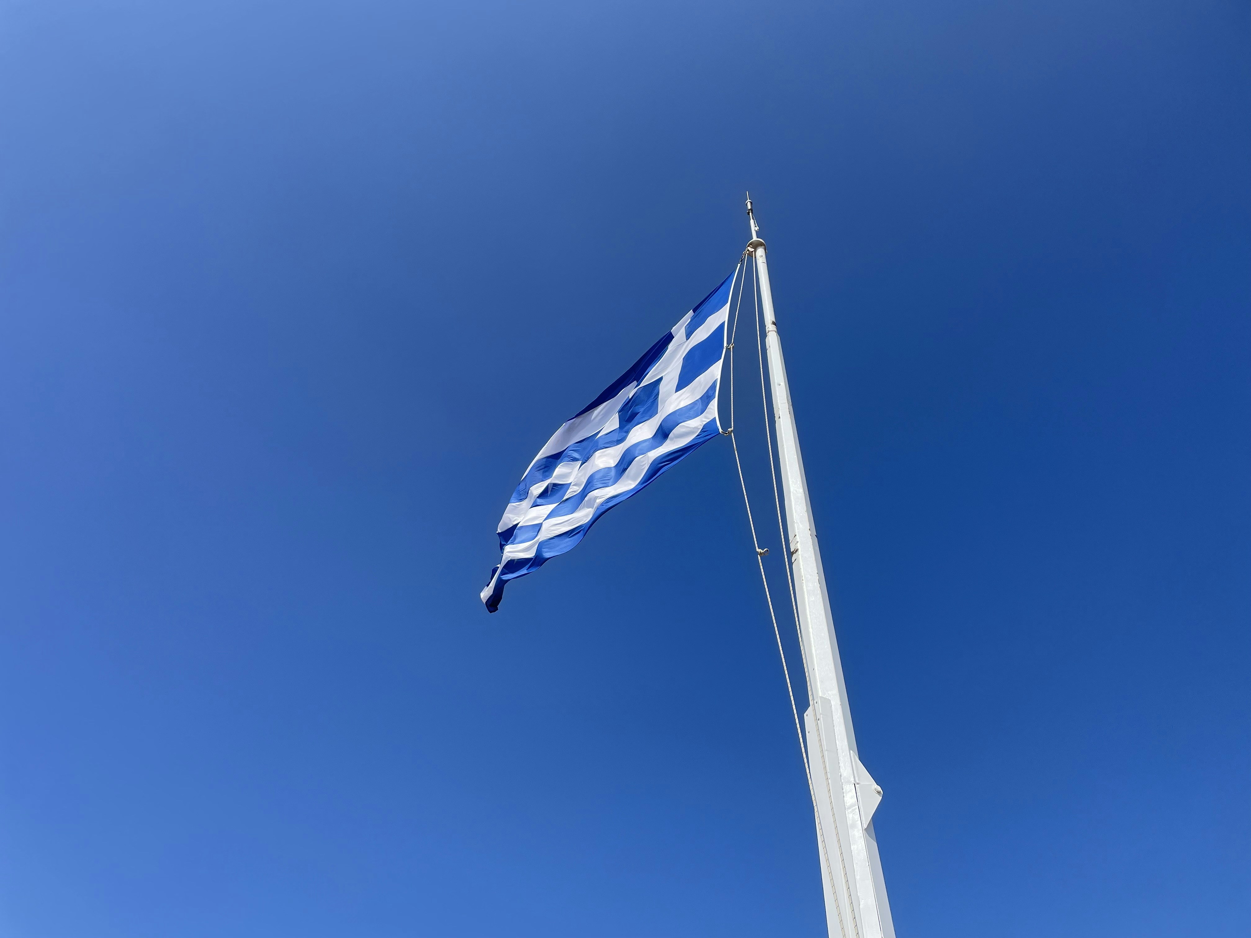 A blue and white flag flying in the wind photo – Free Flag Image on ...