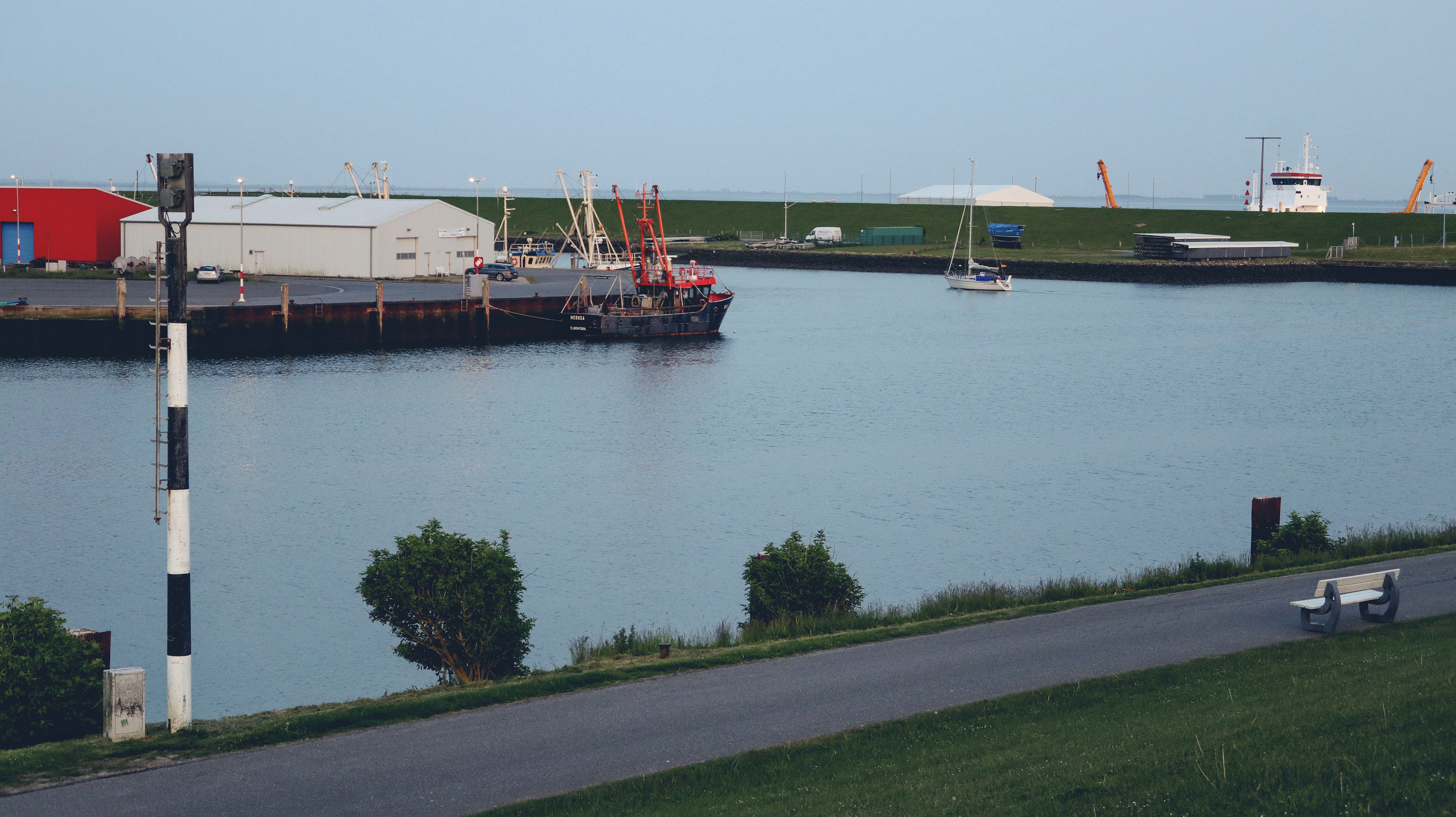 Harbor Edge: Boats at Rest with Distant Cranes on a Quiet Horizon