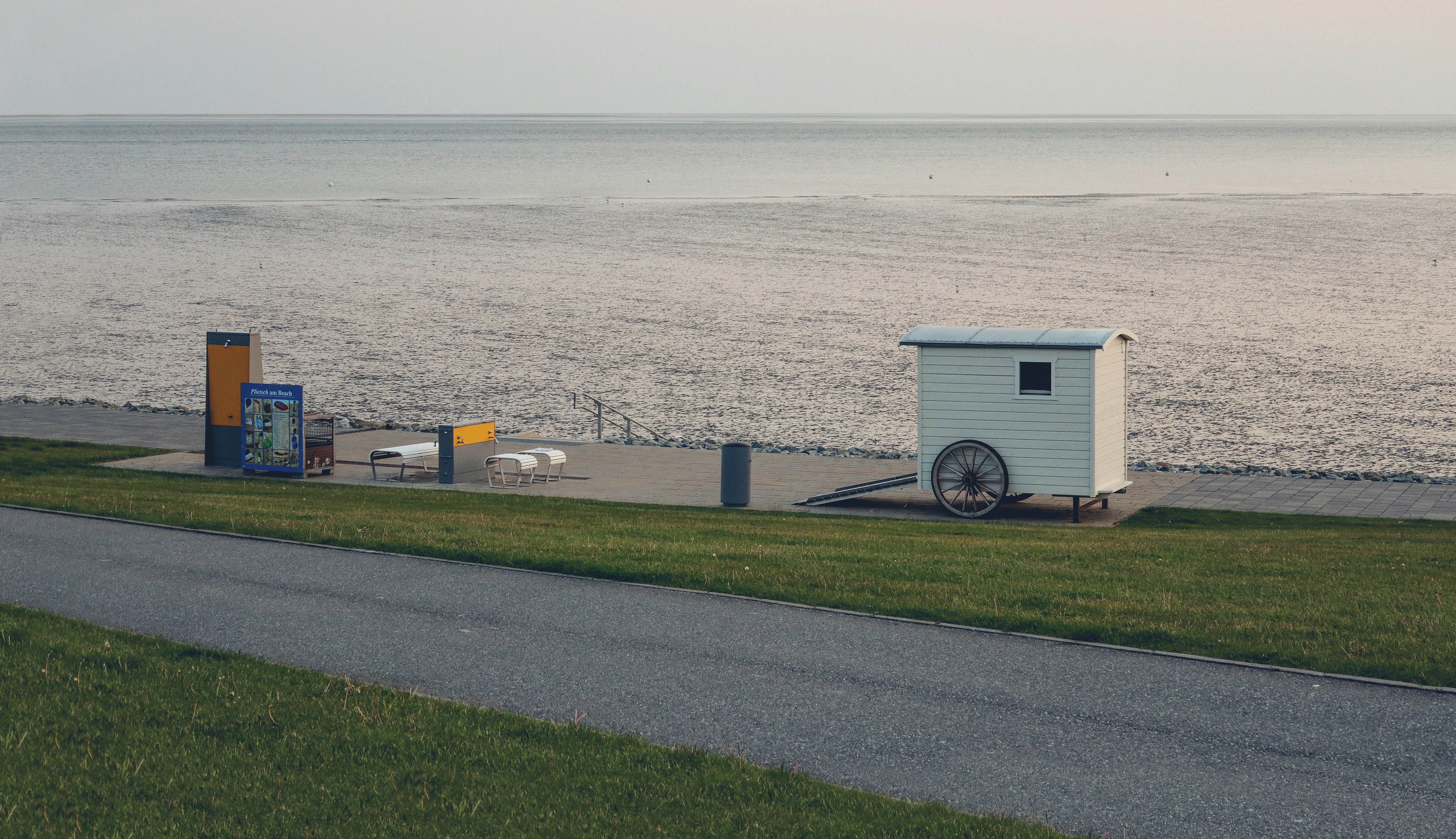 a small white building sitting on the side of a road next to the ocean