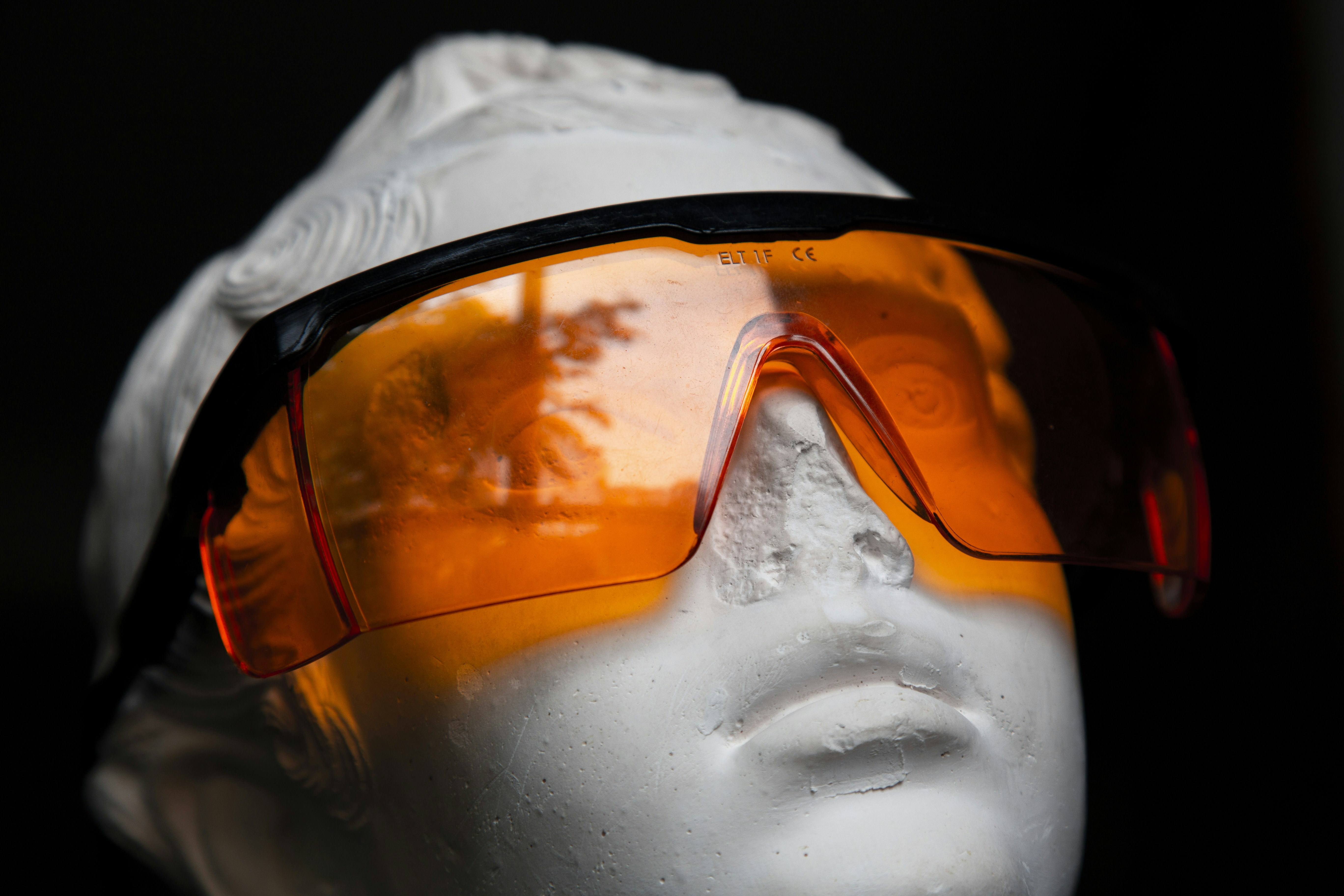 Amber Shield: Close-Up Portrait of a Masked Head in Orange Lens