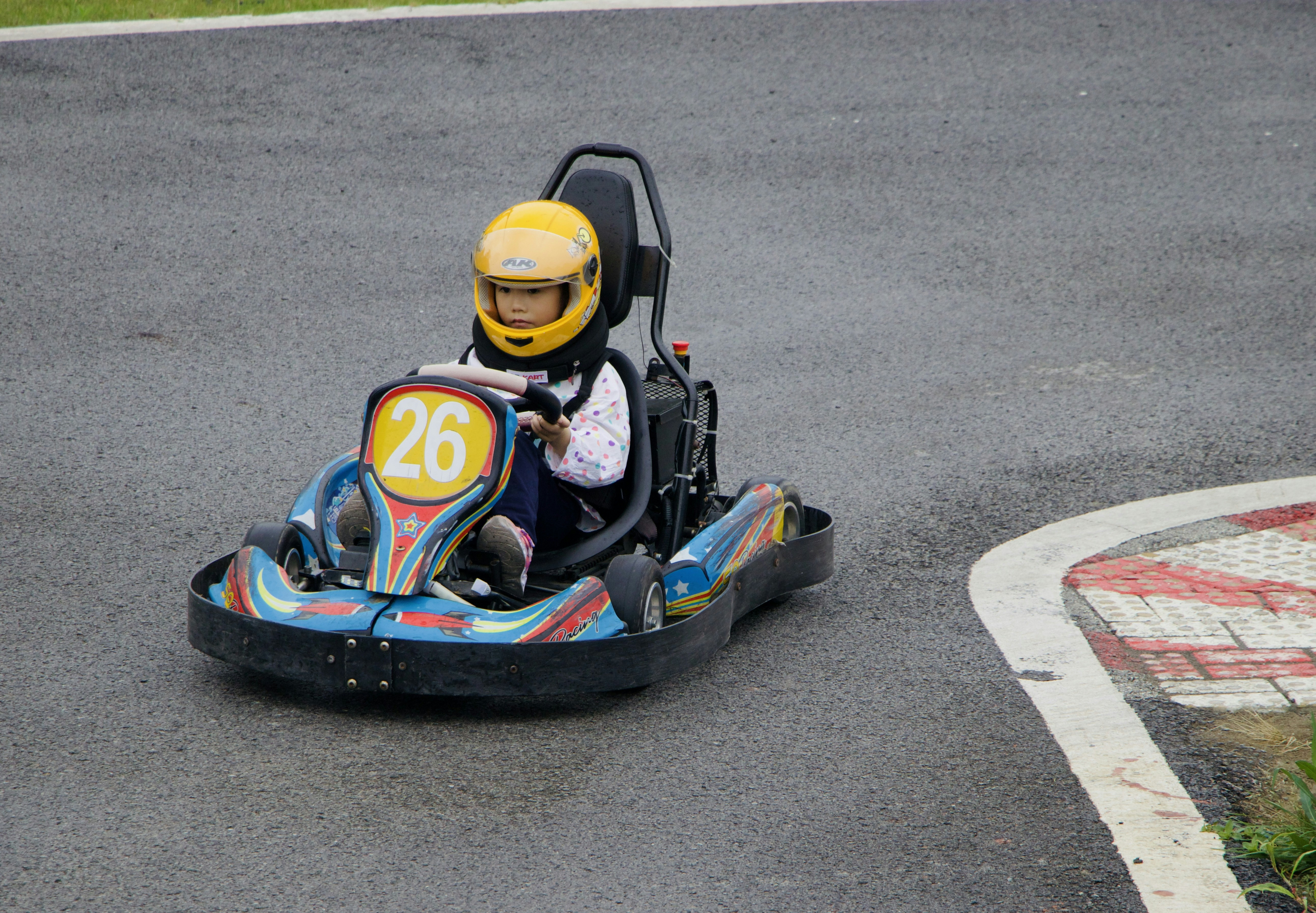 A young boy riding a bumper car down a race track photo – Free Girl ...