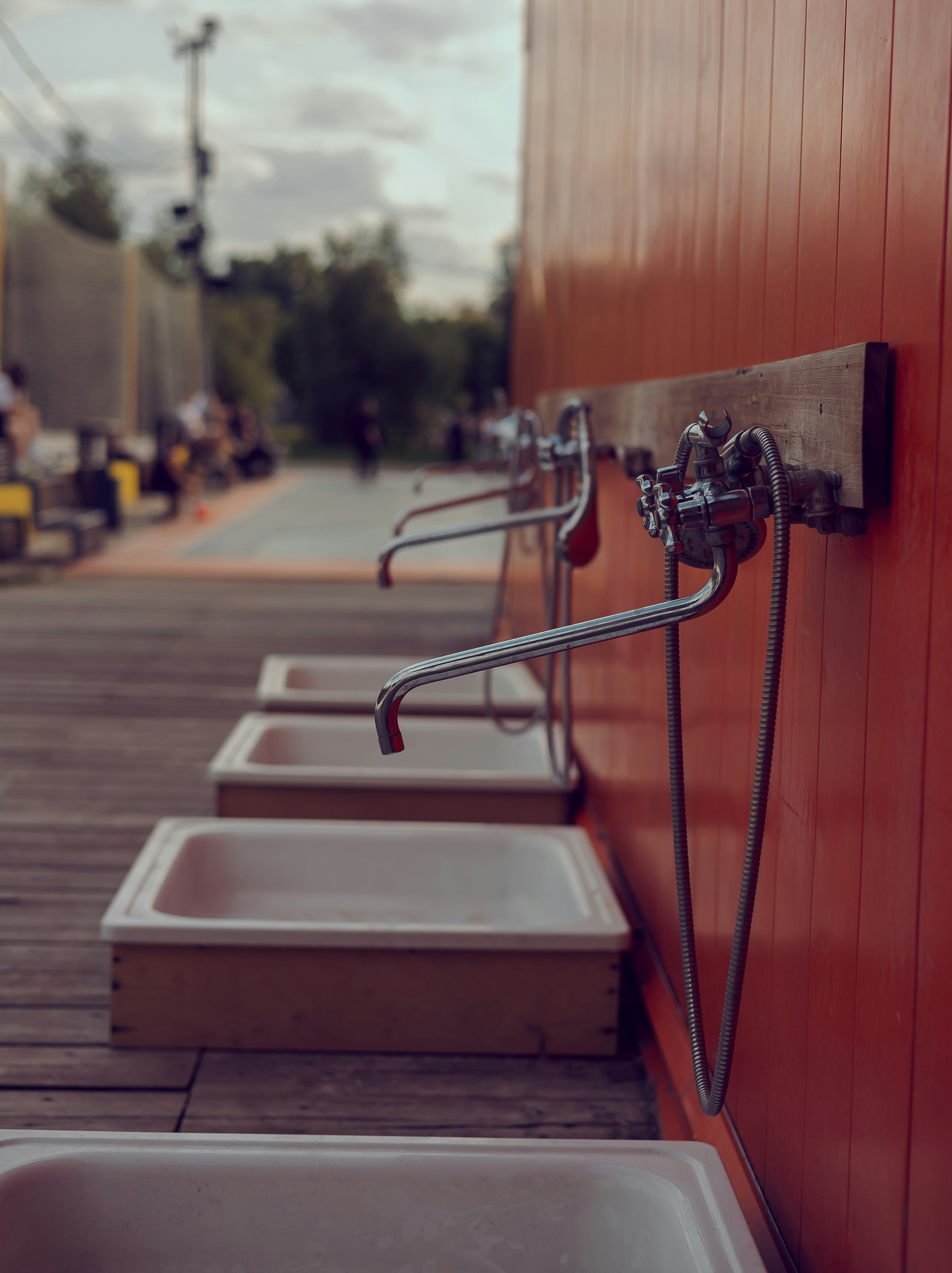 Chrome Rivers by the Red Wall: An Outdoor Sink Corridor