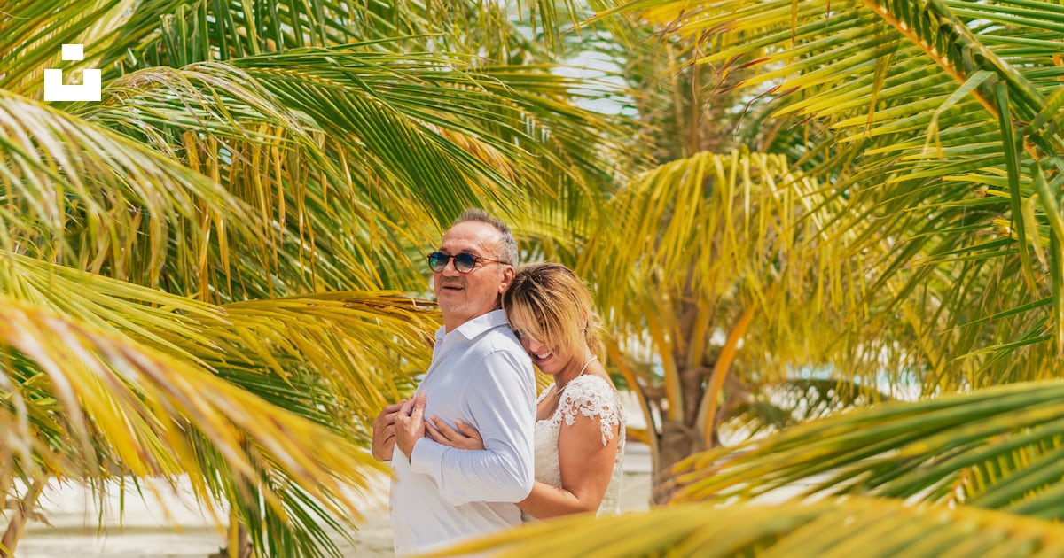 A Man And A Woman Walking On The Beach Under Palm Trees Photo Free Wedding Couple Image On