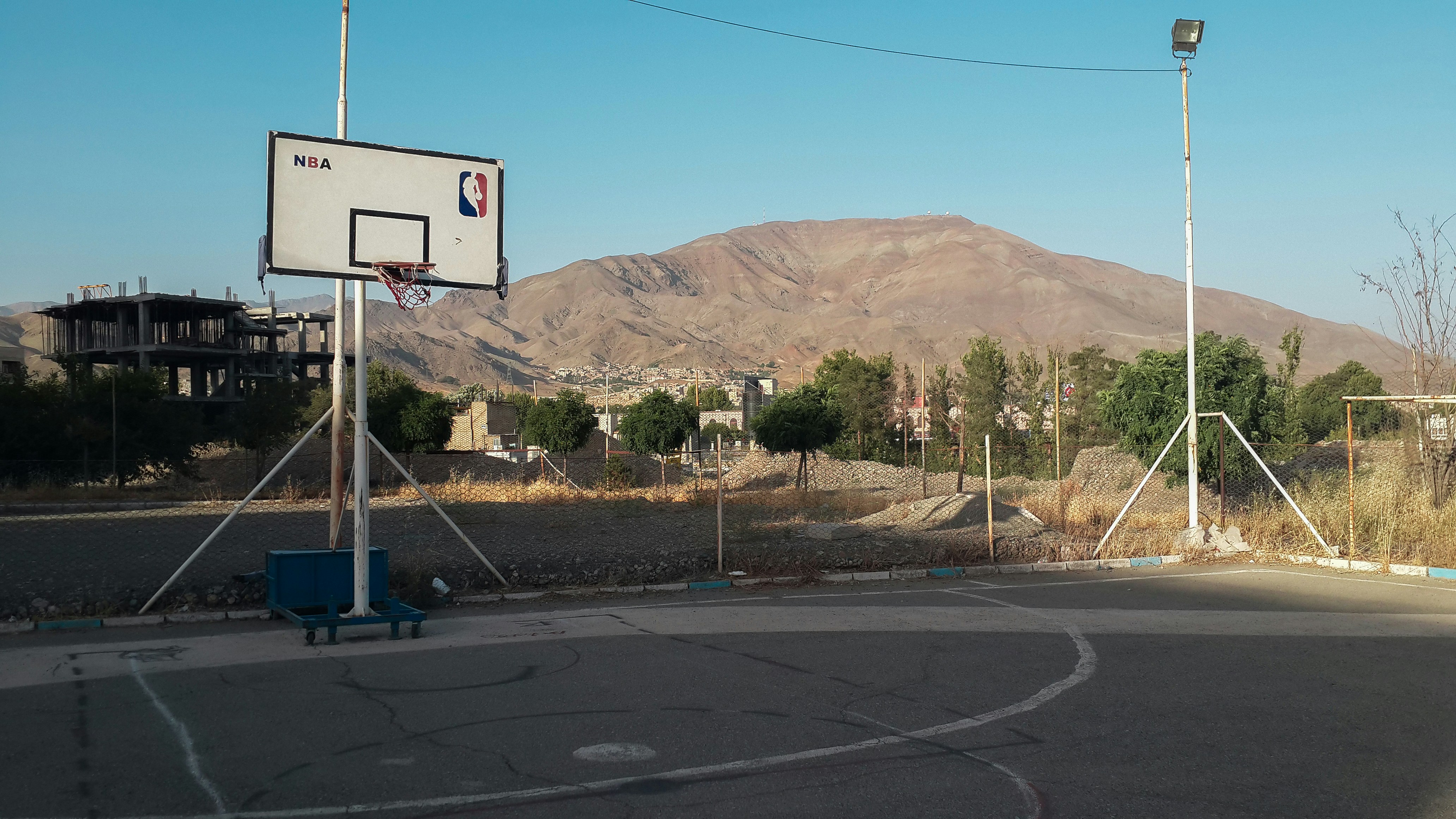 Outdoor basketball court with a mountain backdrop under a clear blue sky.