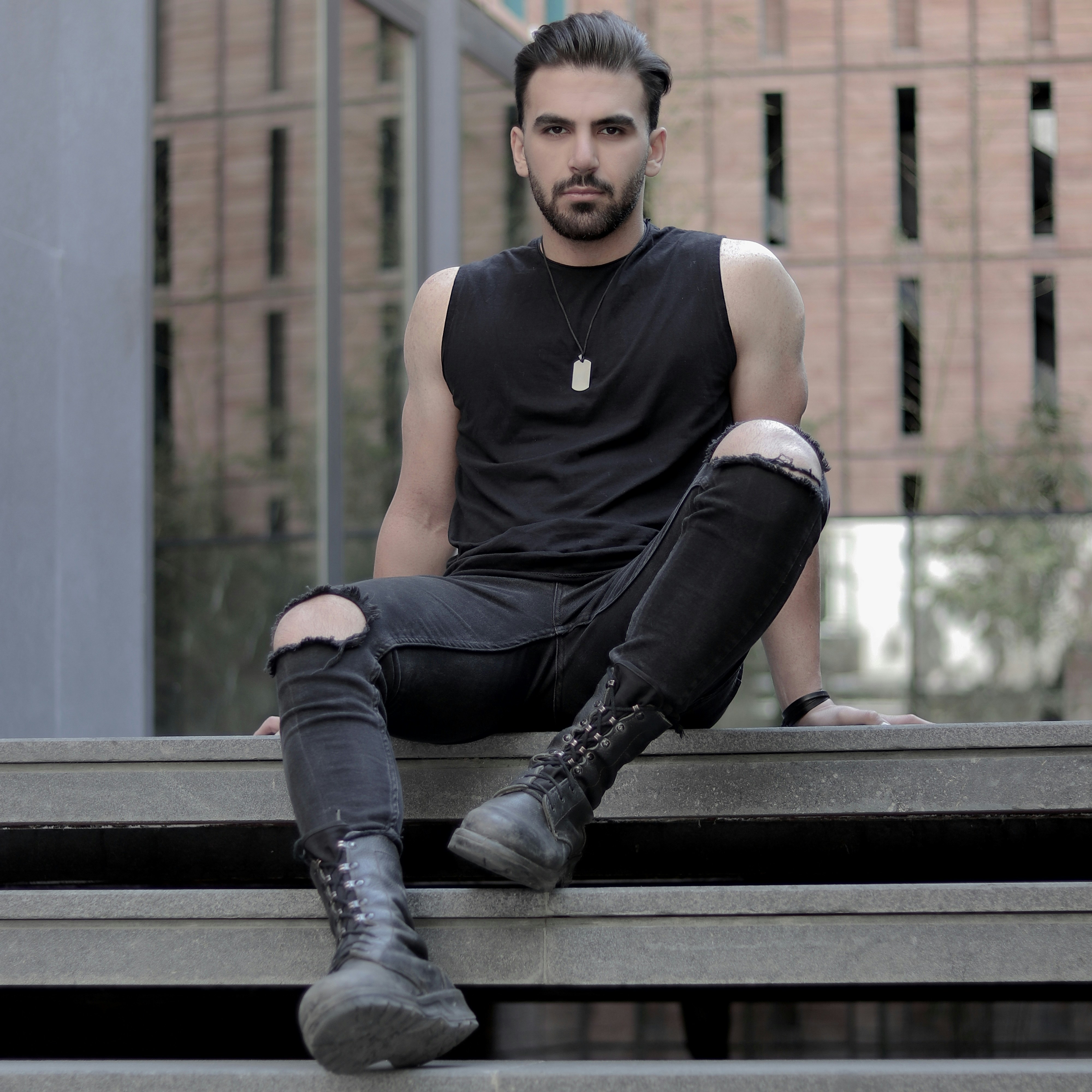 A man sitting on a ledge with his legs crossed photo – Free Person ...