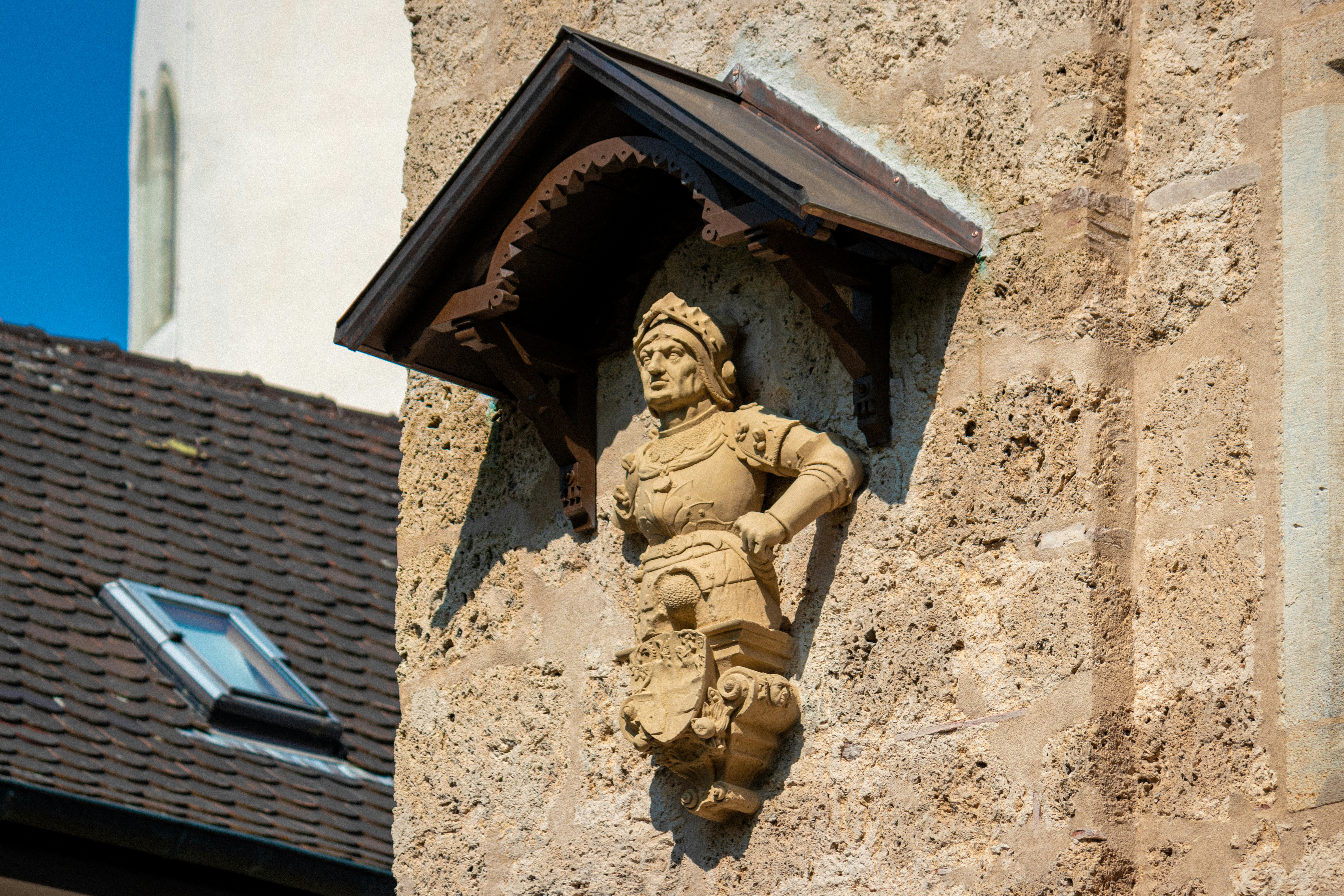 Stone Sentinel Under a Tiny Wooden Canopy on Sunlit Masonry