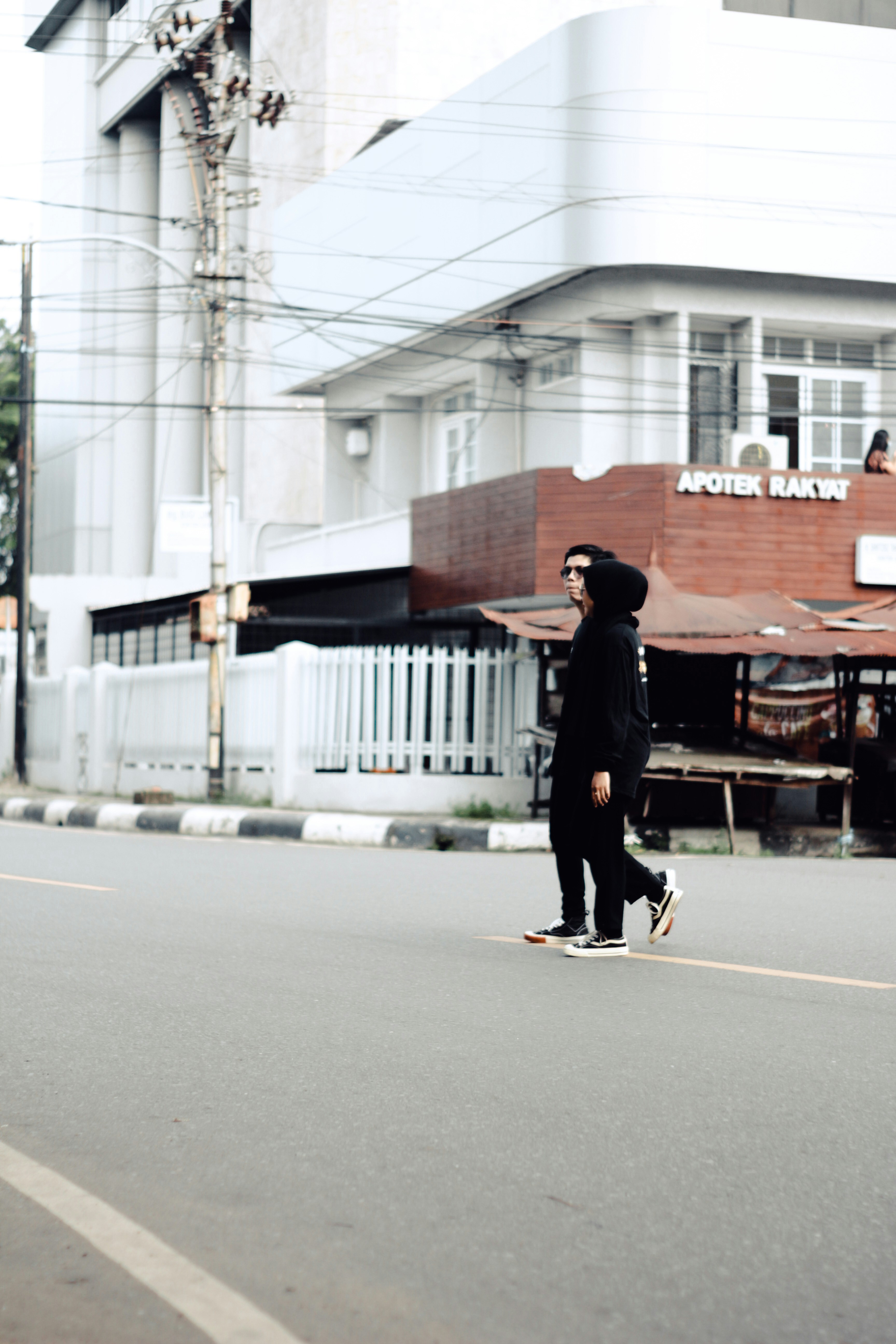 City Street Stroll: Hooded Pair Crossing Quiet Pavement