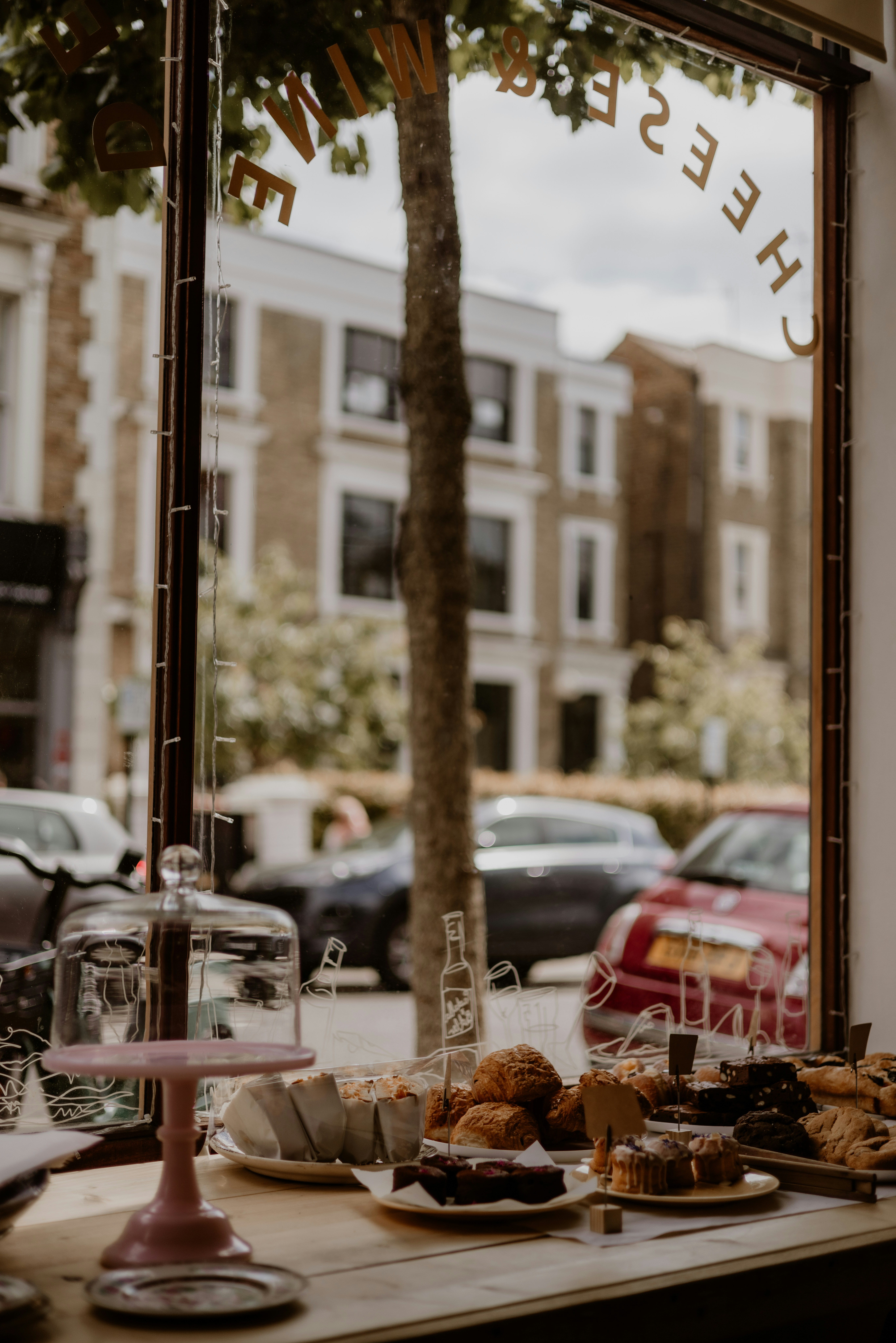 Sunlit Pastries at a Windowed Café, Framing a Quiet Urban Street