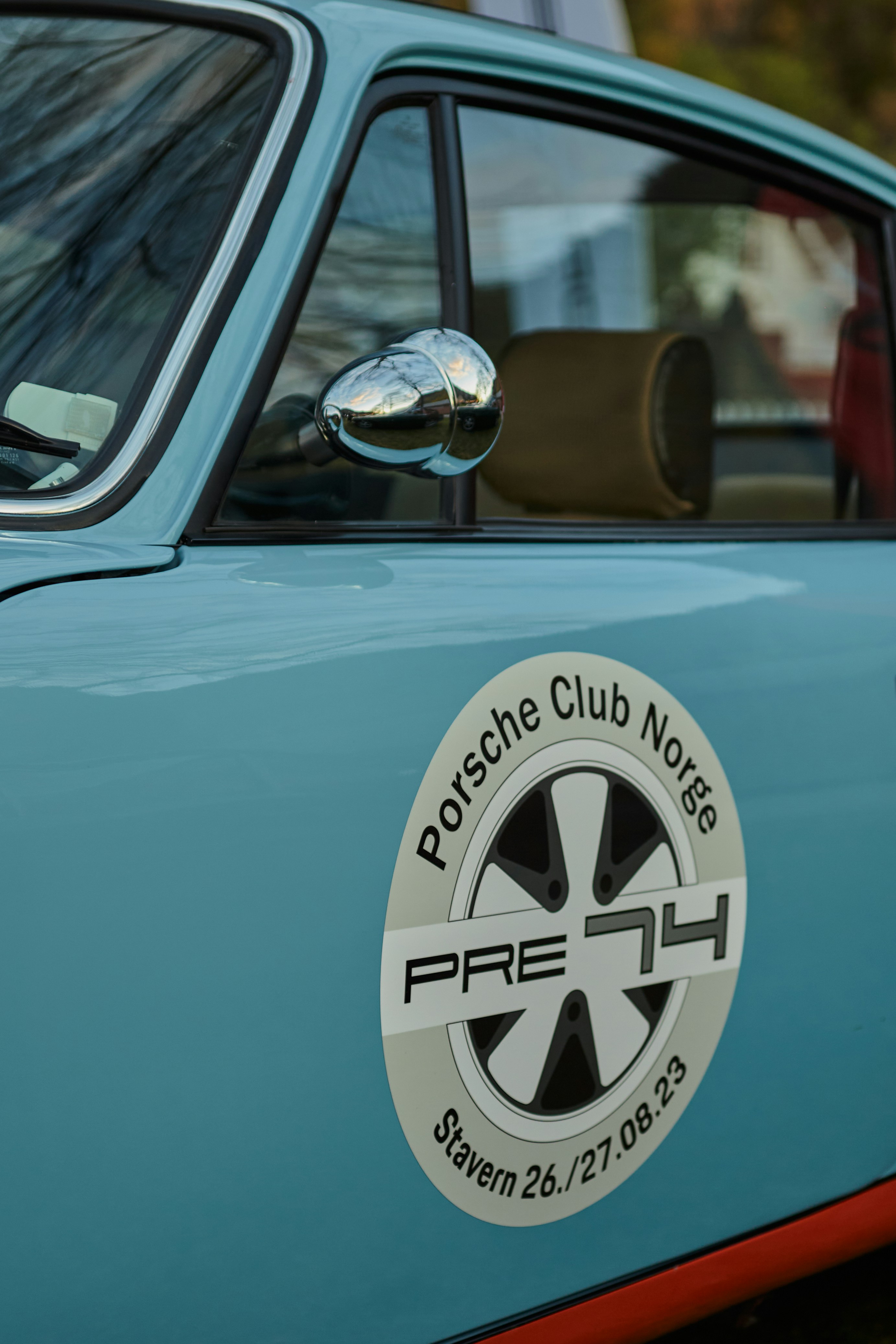 Teal Vintage Porsche Club Emblem on a Sunlit Door