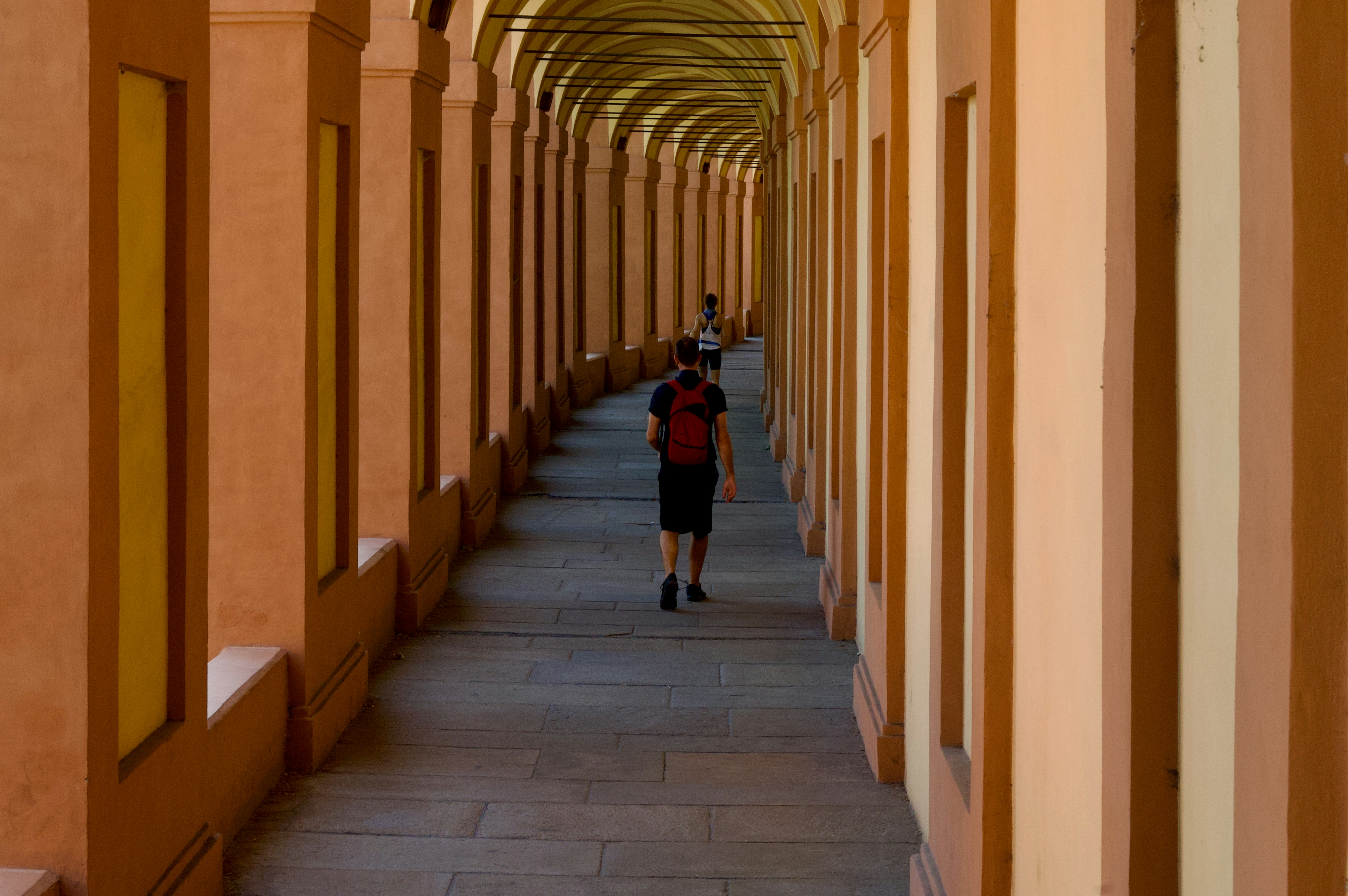 Foto Una persona caminando por un largo pasillo entre dos edificios – Imagen Persona gratis en ...