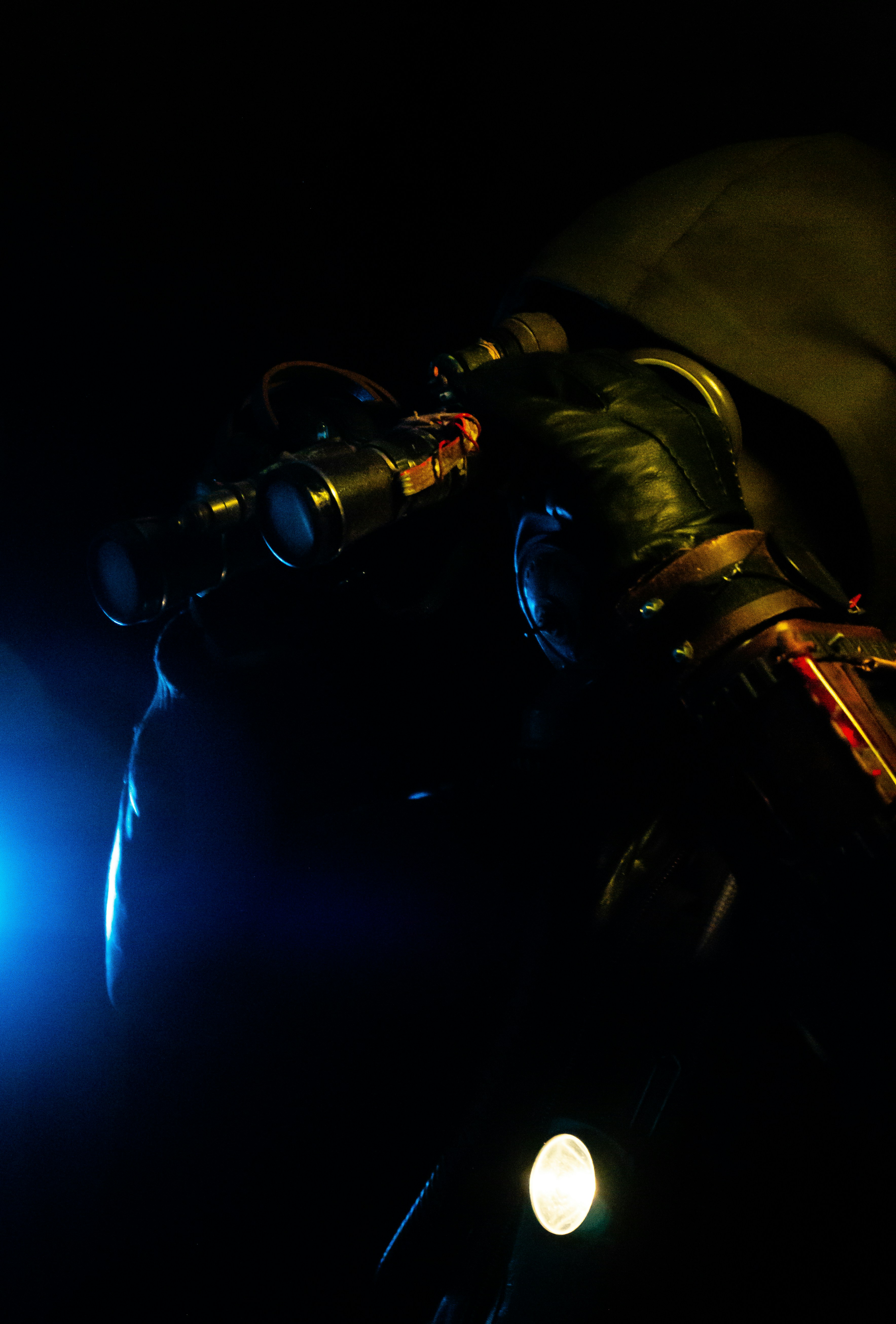Nightscope Grip: A Gloved Hand Steadies a Scoped Rifle Under Blue Neon