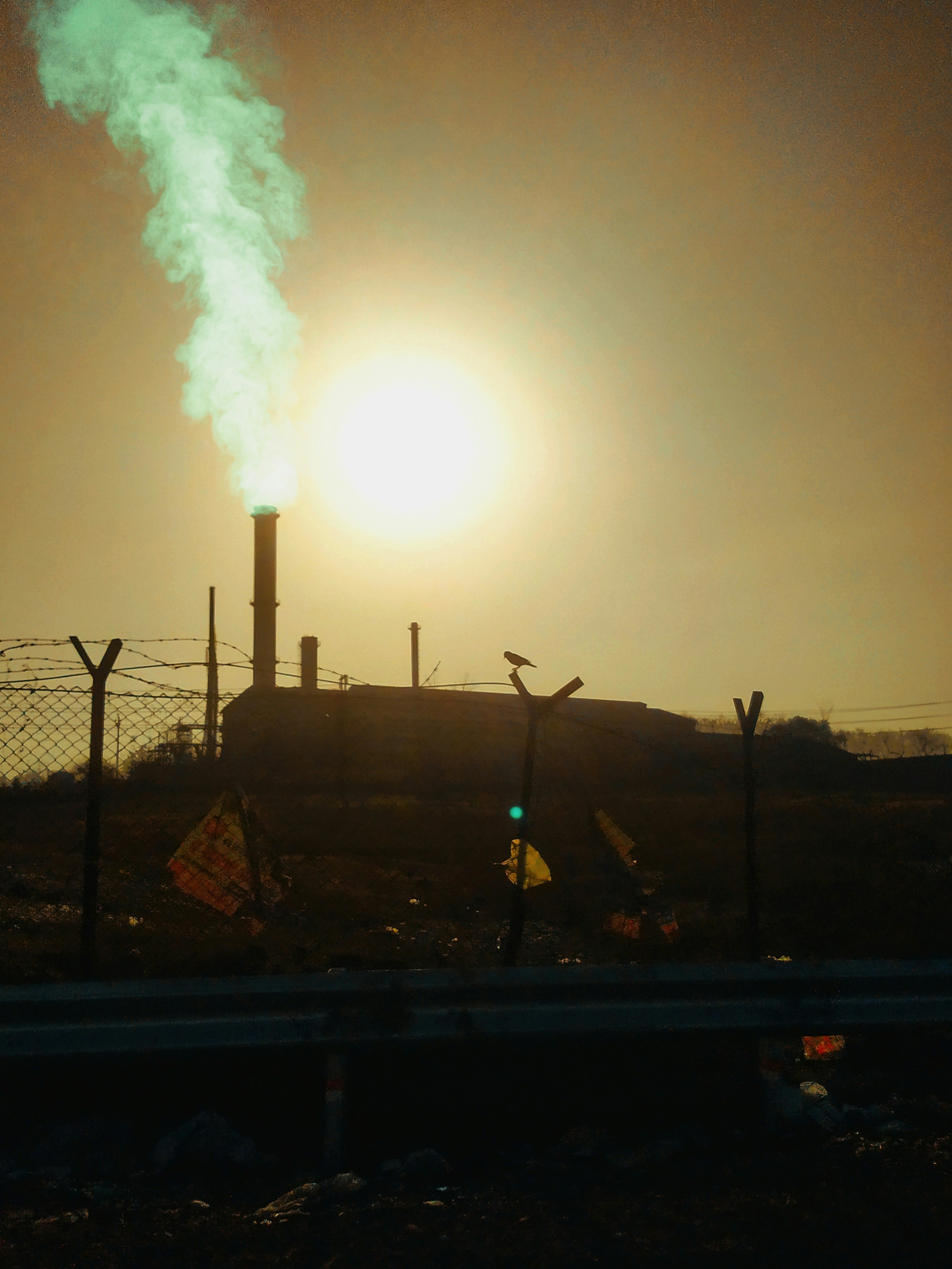 Industrial Sunset: Smoke, Barbed Wire, and a Silhouette