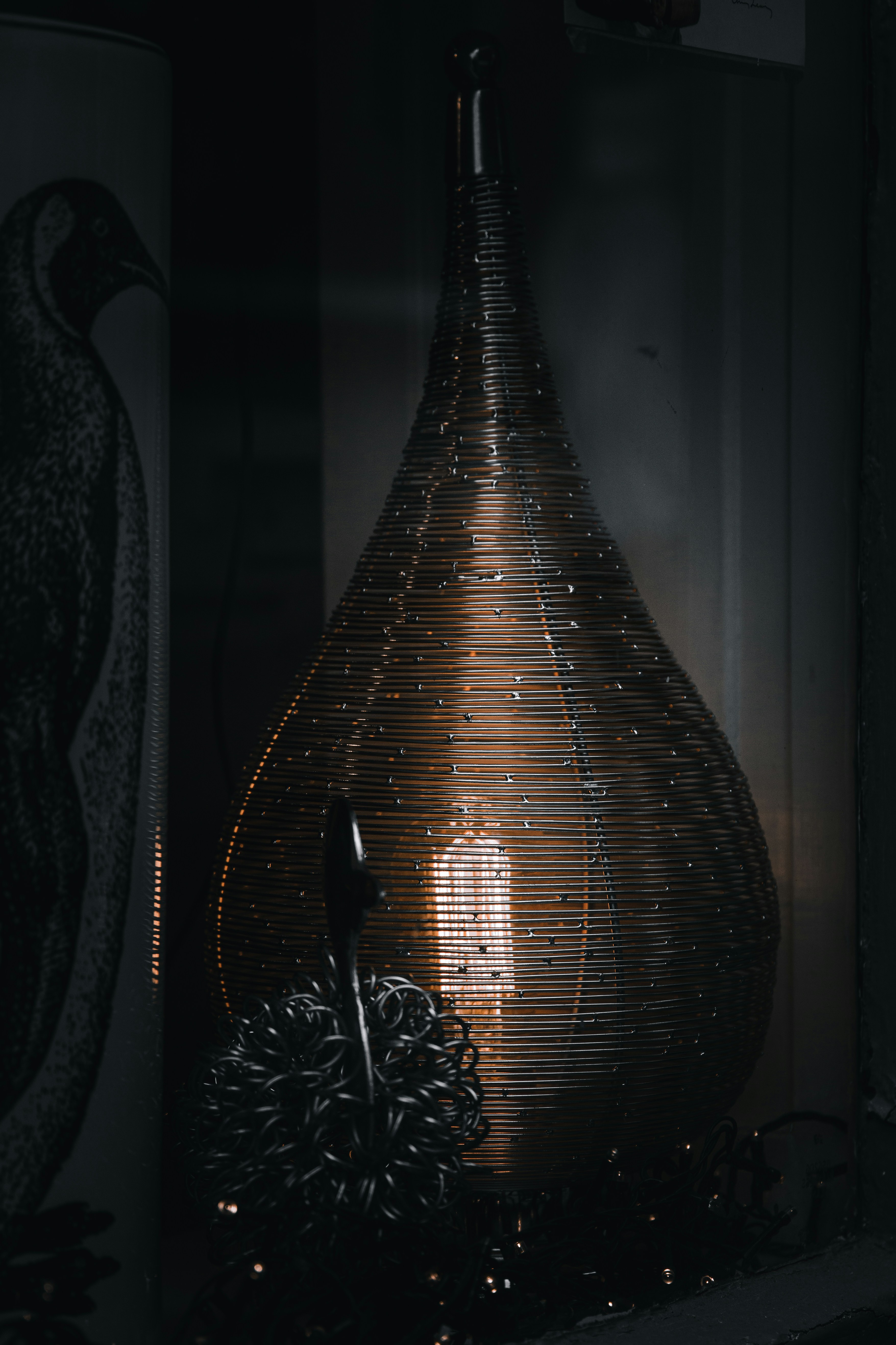 A Teardrop Woven Lamp Emitting a Gentle Glow in a Shadowed Nook