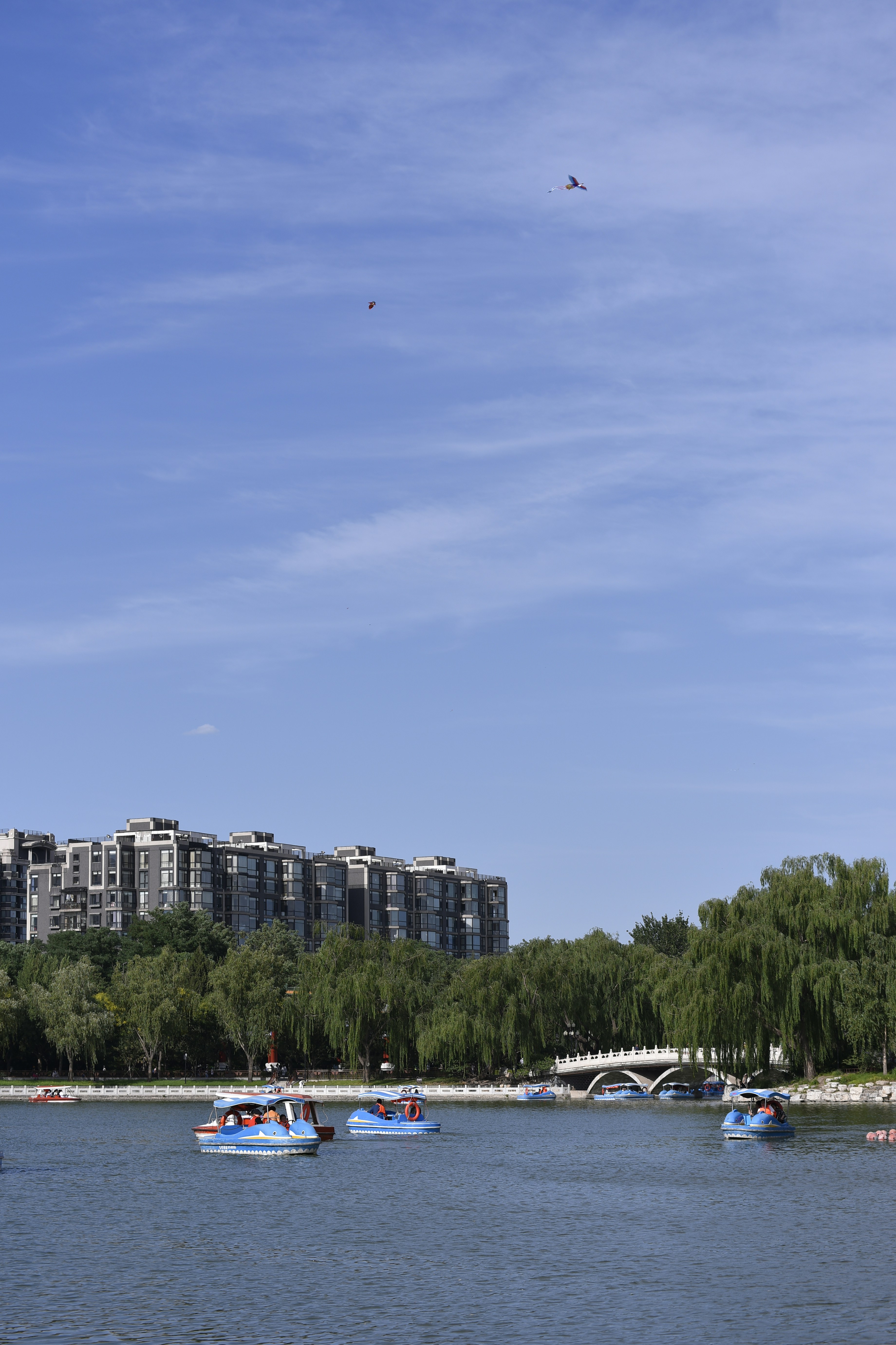 Riverside Wake: Boats Drifting Before a Modern Cityscape