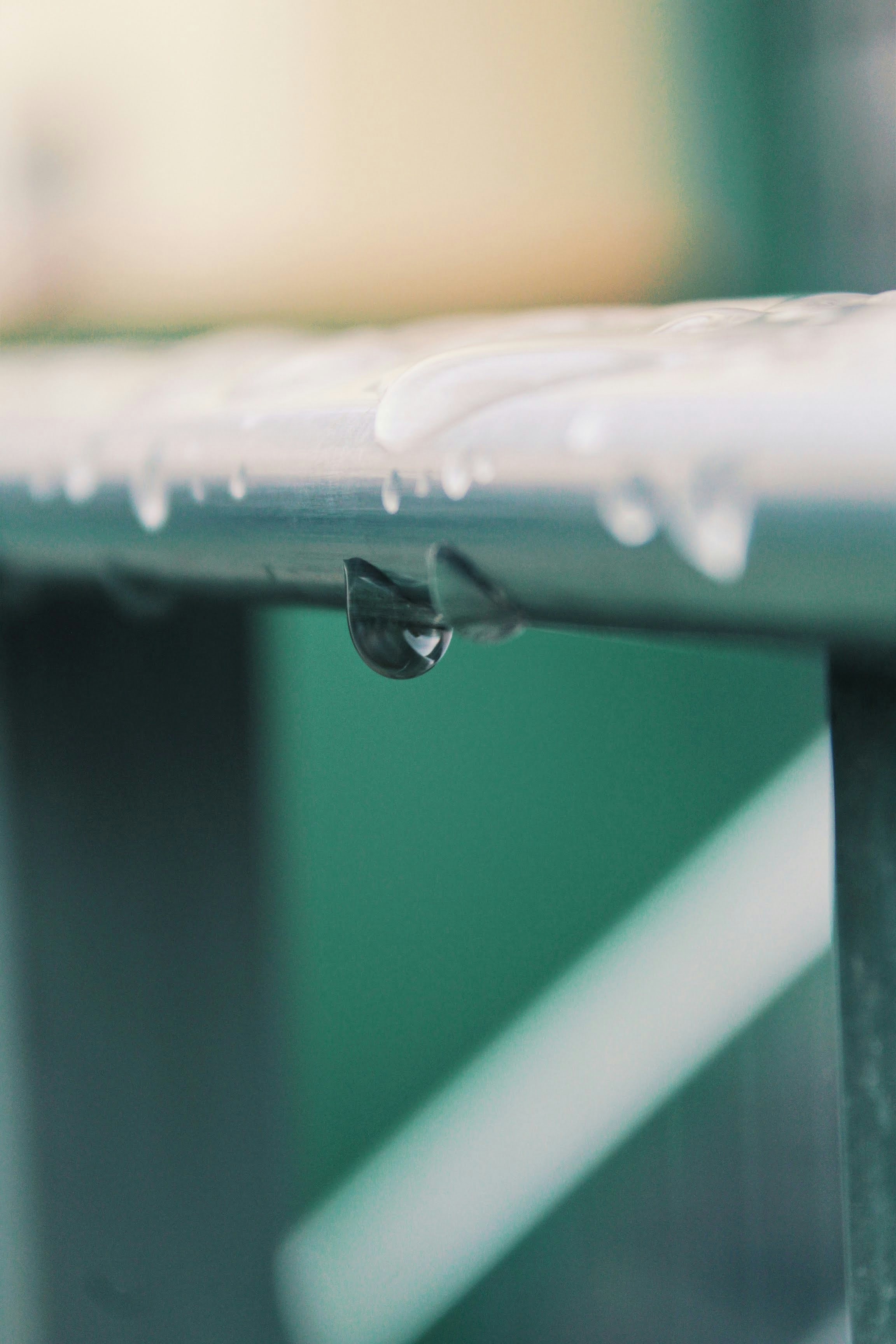 A droplet clings to the edge of a rain-slick railing