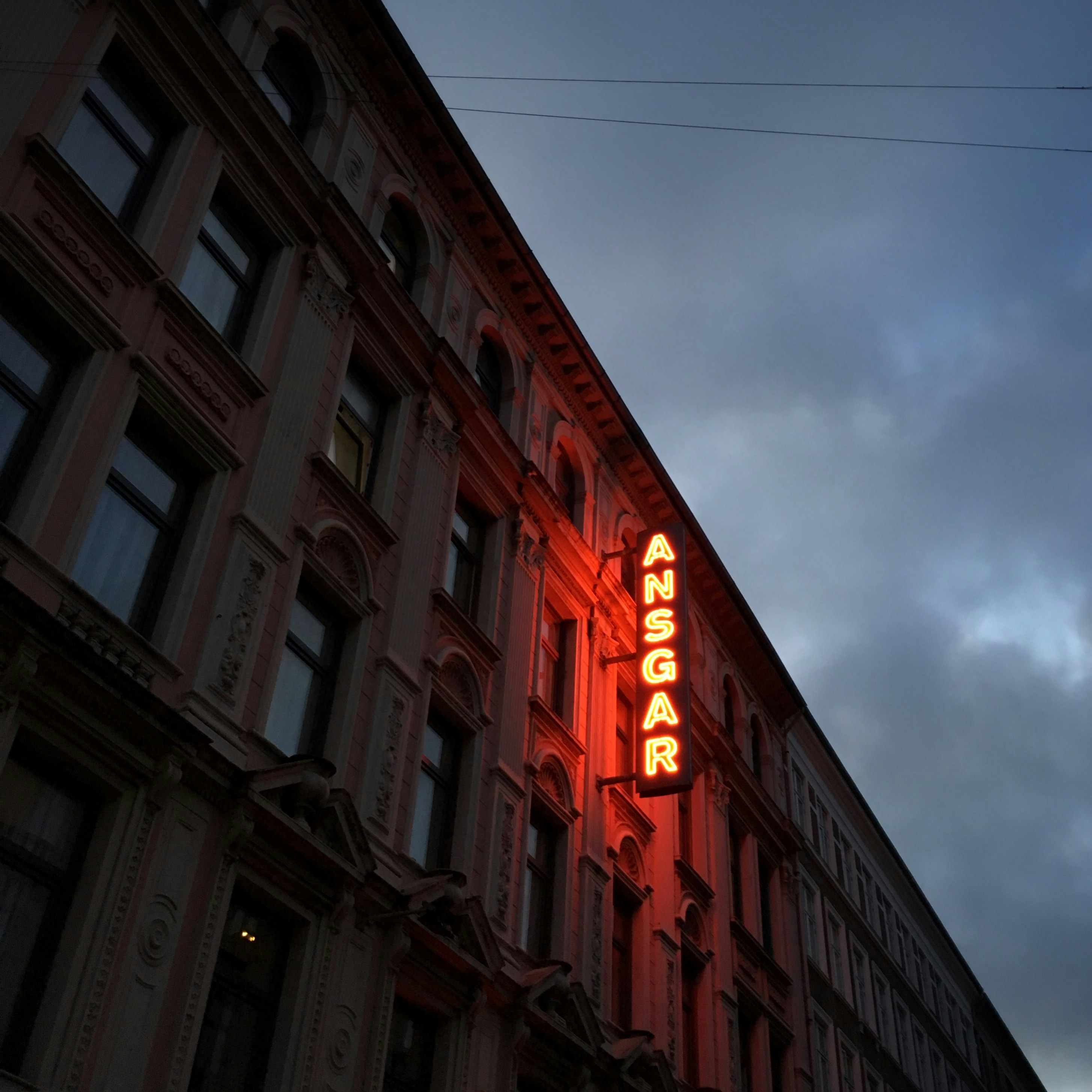 Foto Un gran edificio con un letrero de neón en su lado – Imagen Hotel Ansgar gratis en Unsplash