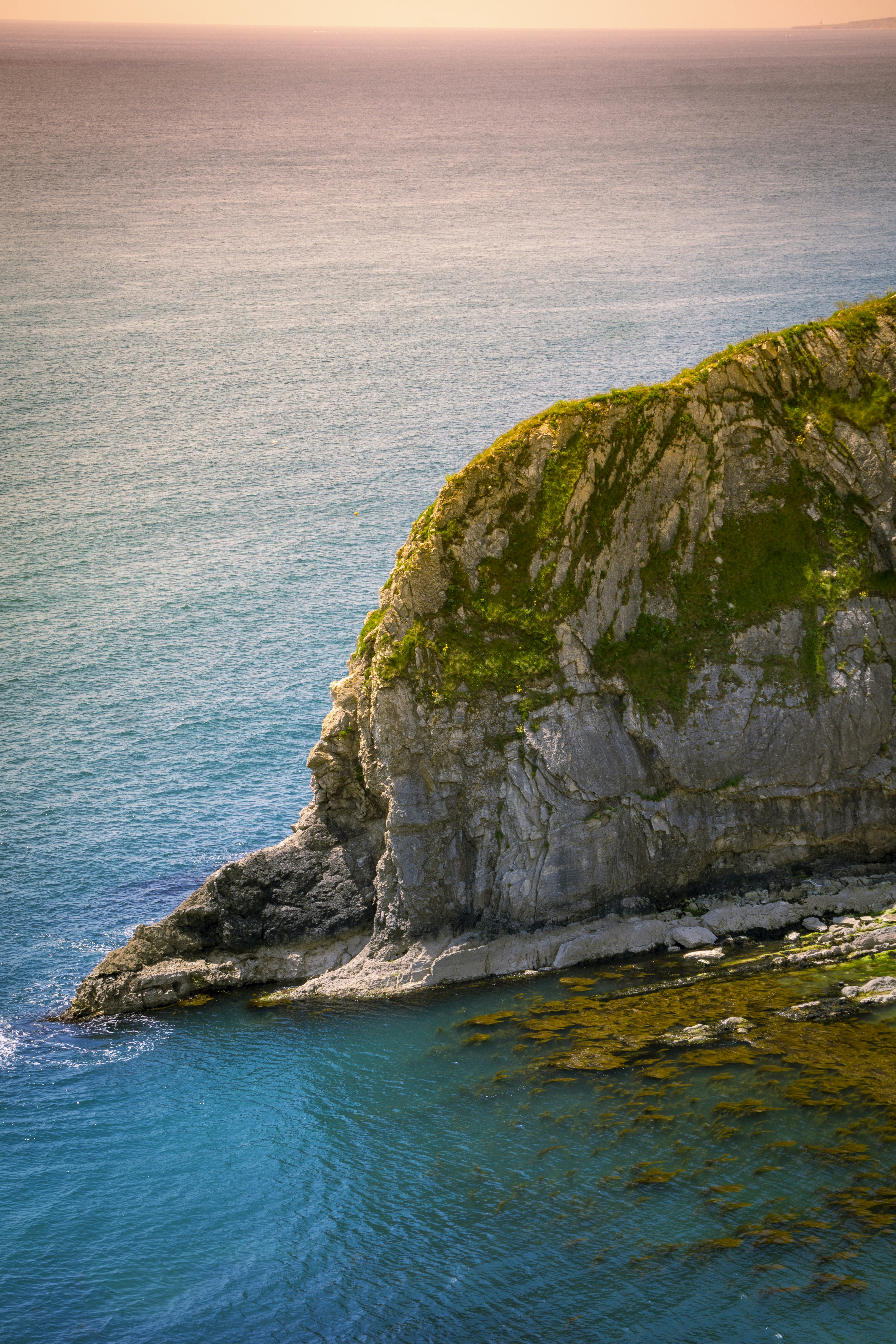 Sunlit Cliff Edge Above Quiet Teal Waters