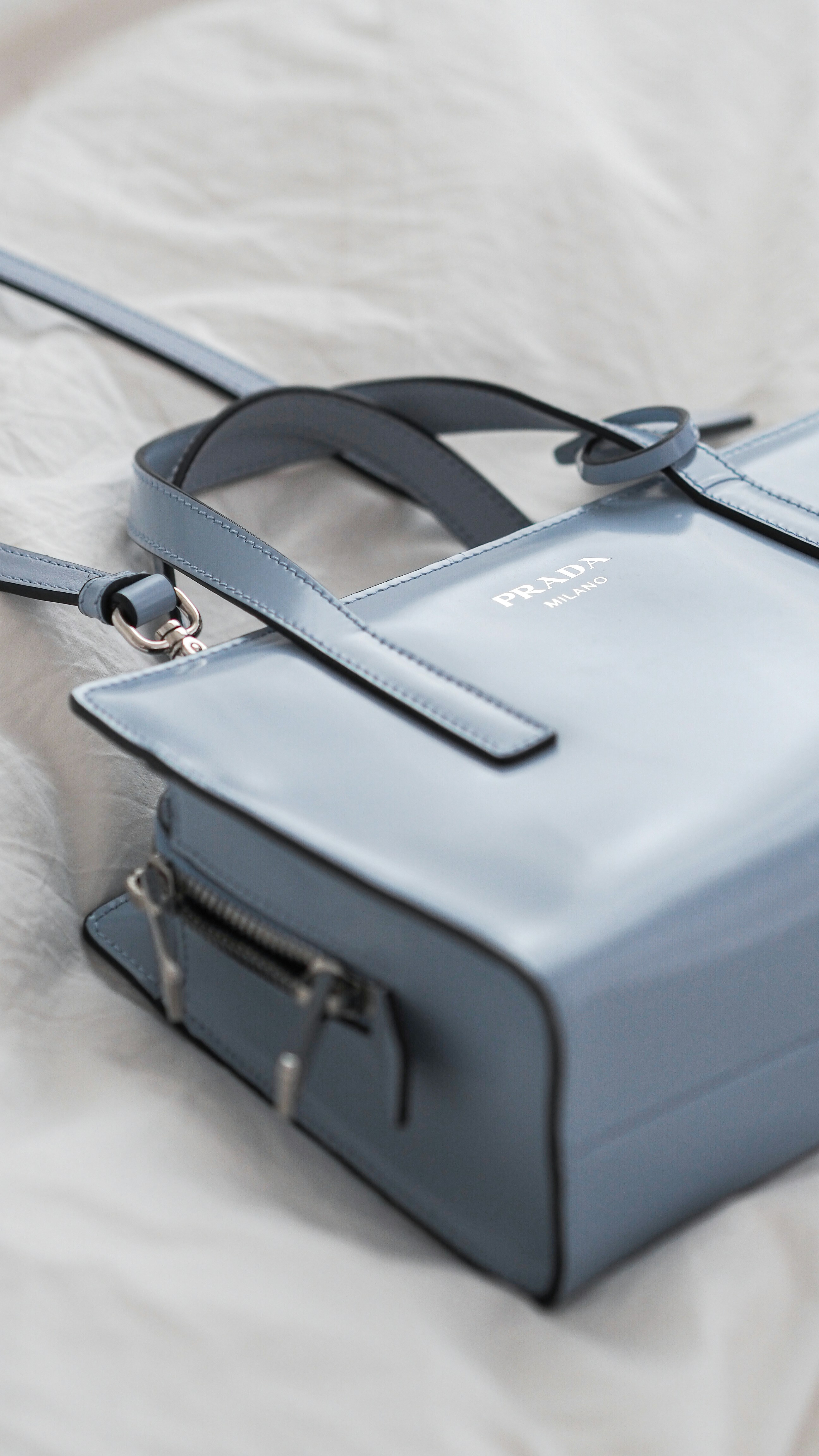 Soft blue Prada Crossbody Resting on a Quiet Bed Sheet