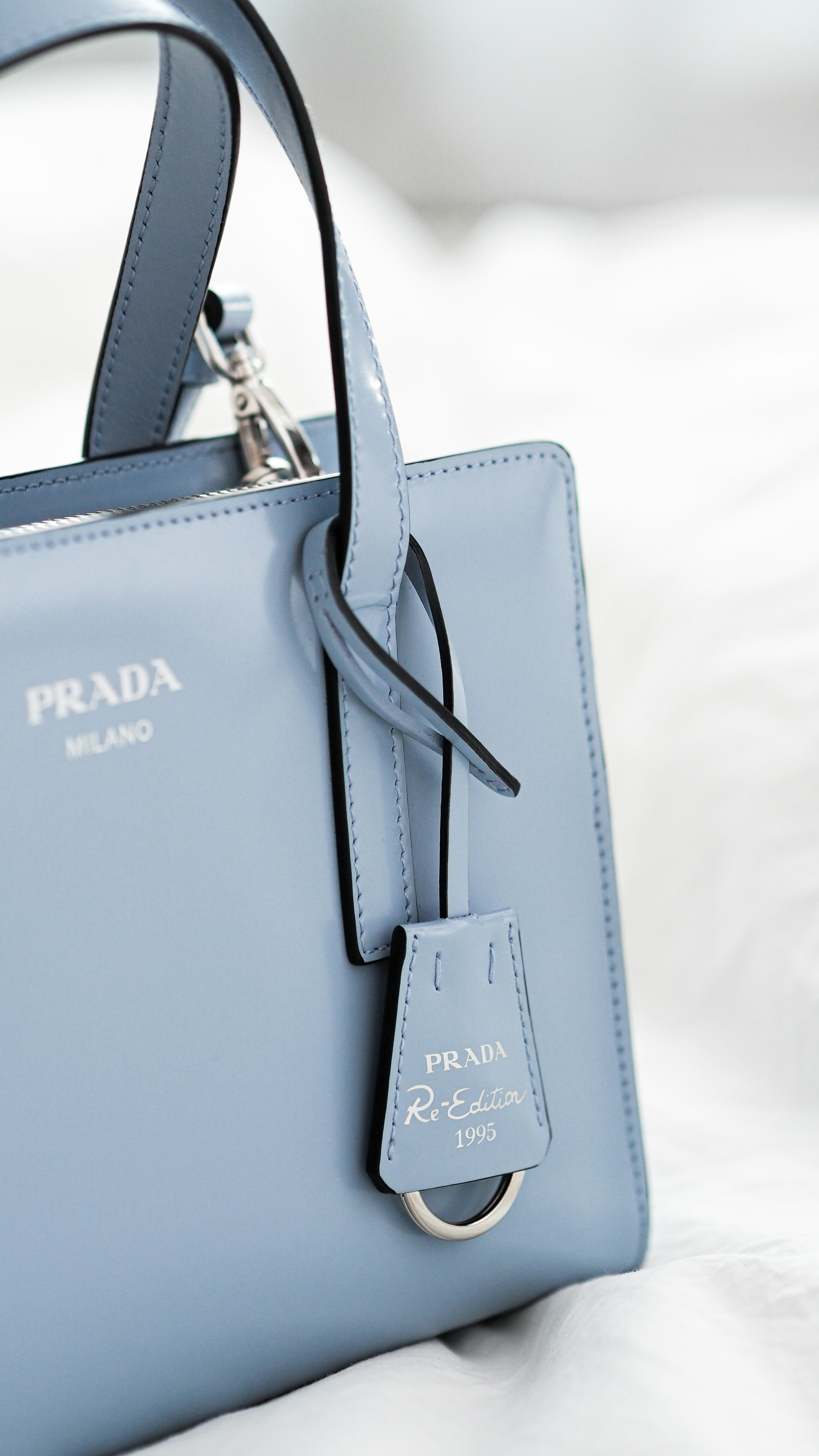 A blue prada bag sitting on top of a bed photo – Free Paris Image on ...