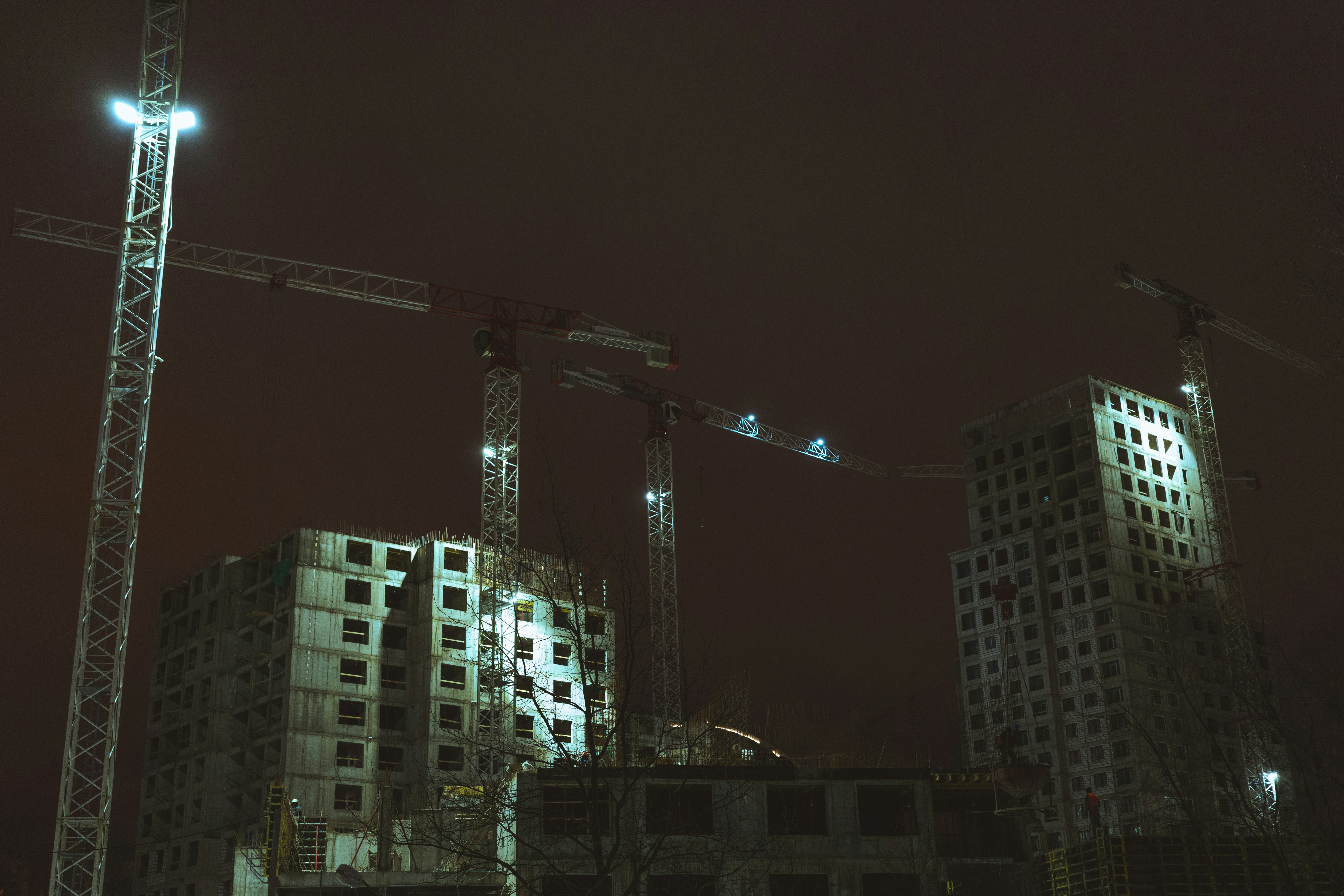 Night Construction: Cranes Framing a Skeleton City under Neon Glow