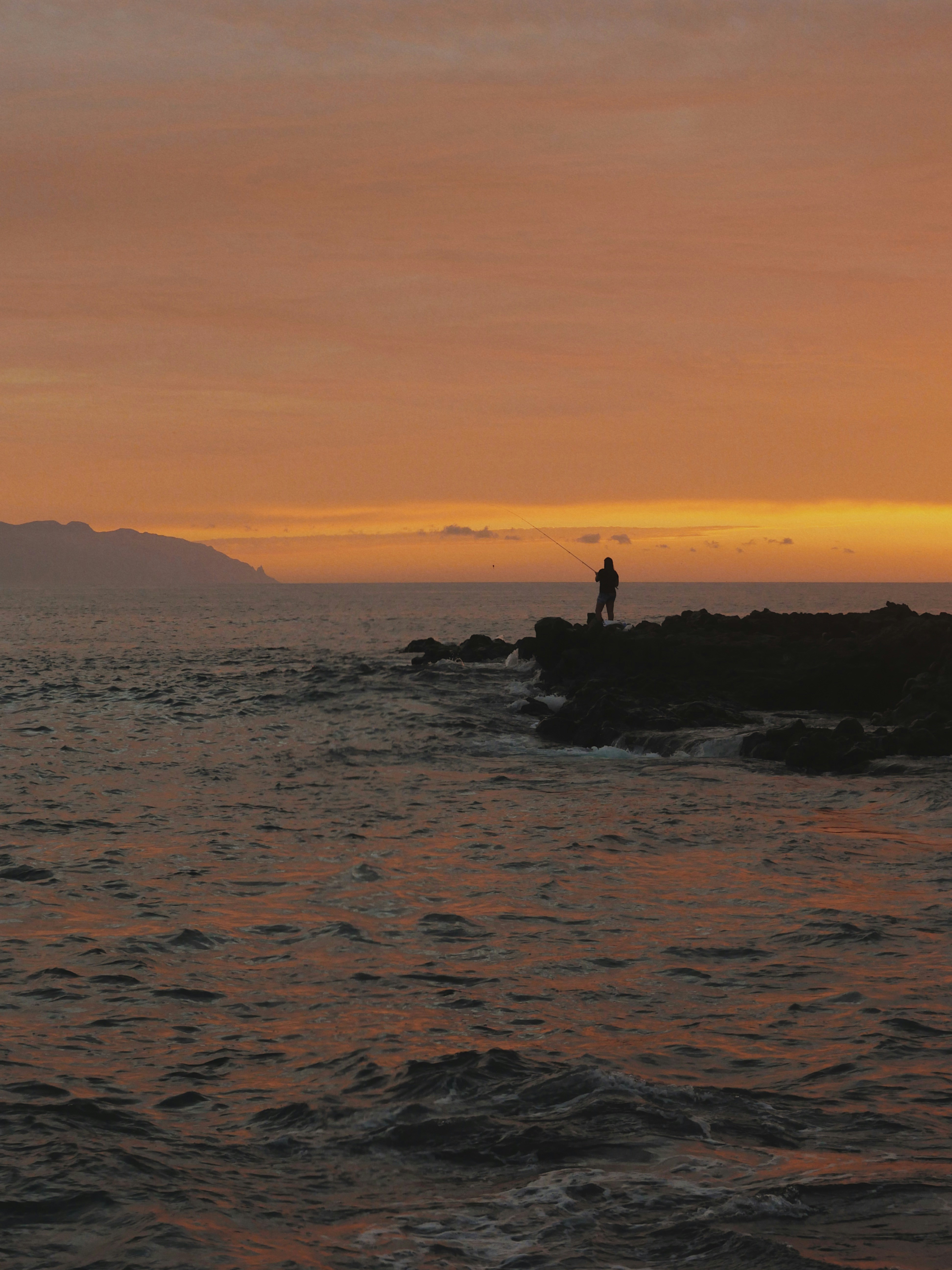 Dusk Angler on a Rocky Seacliff