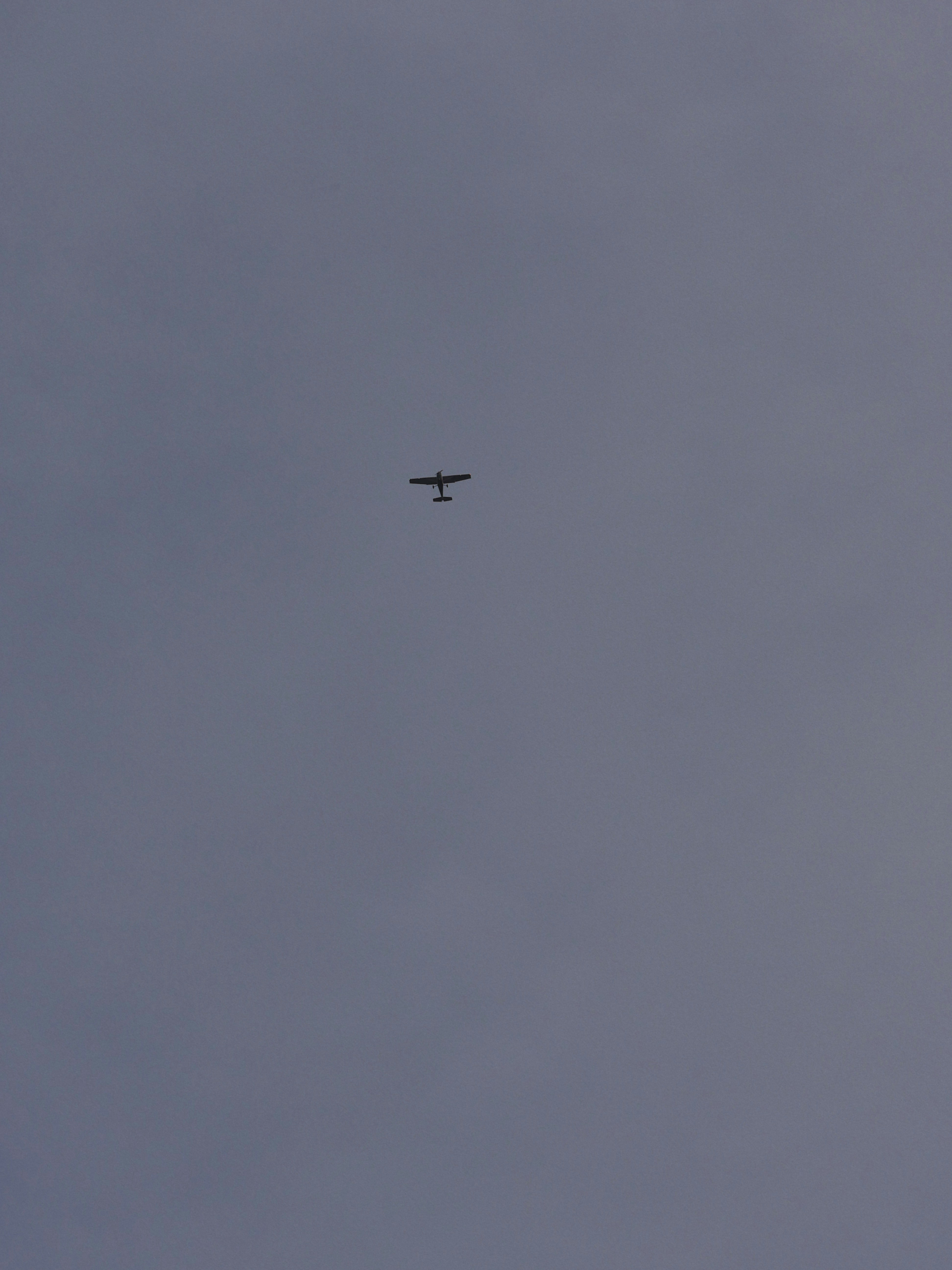 Small aircraft silhouetted against an expansive gray sky.
