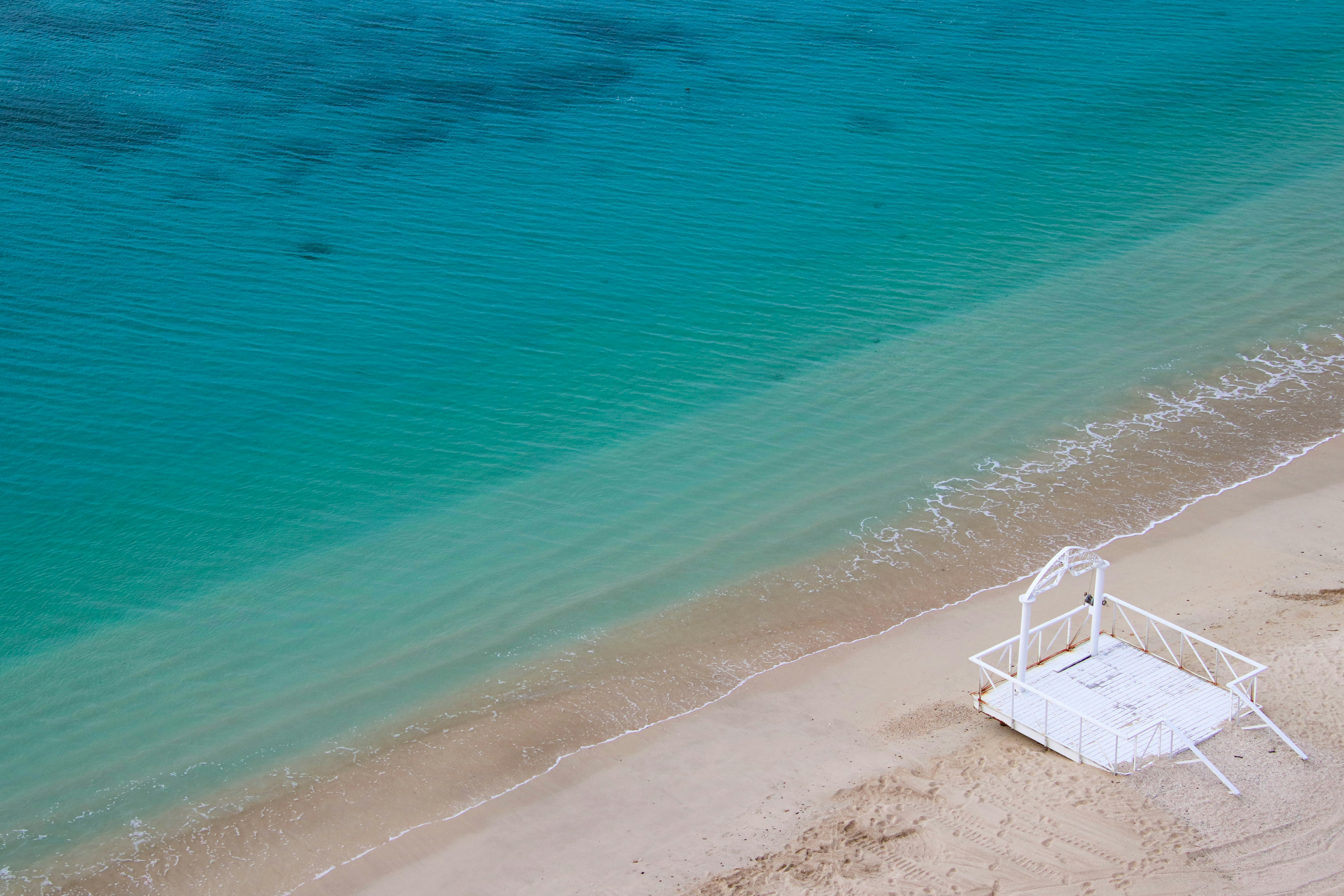 An aerial view of a beach with a chair and umbrella photo – Free Sea ...