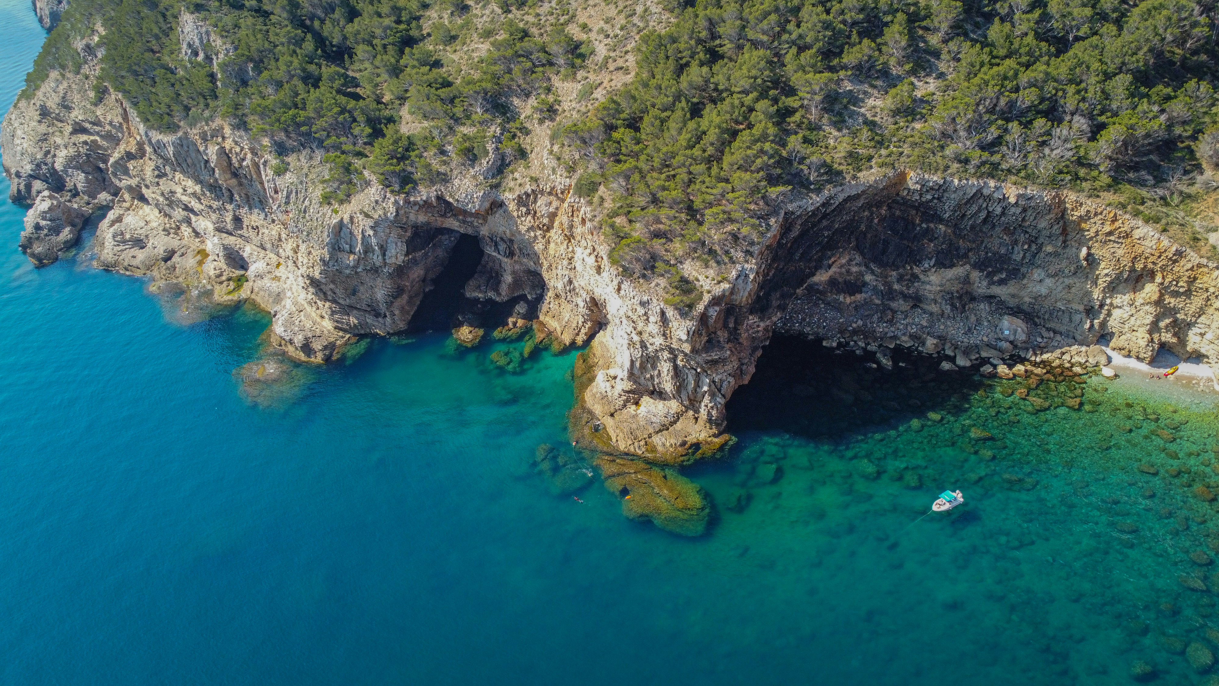 An aerial view of a beach with a boat in the water photo – Free ...