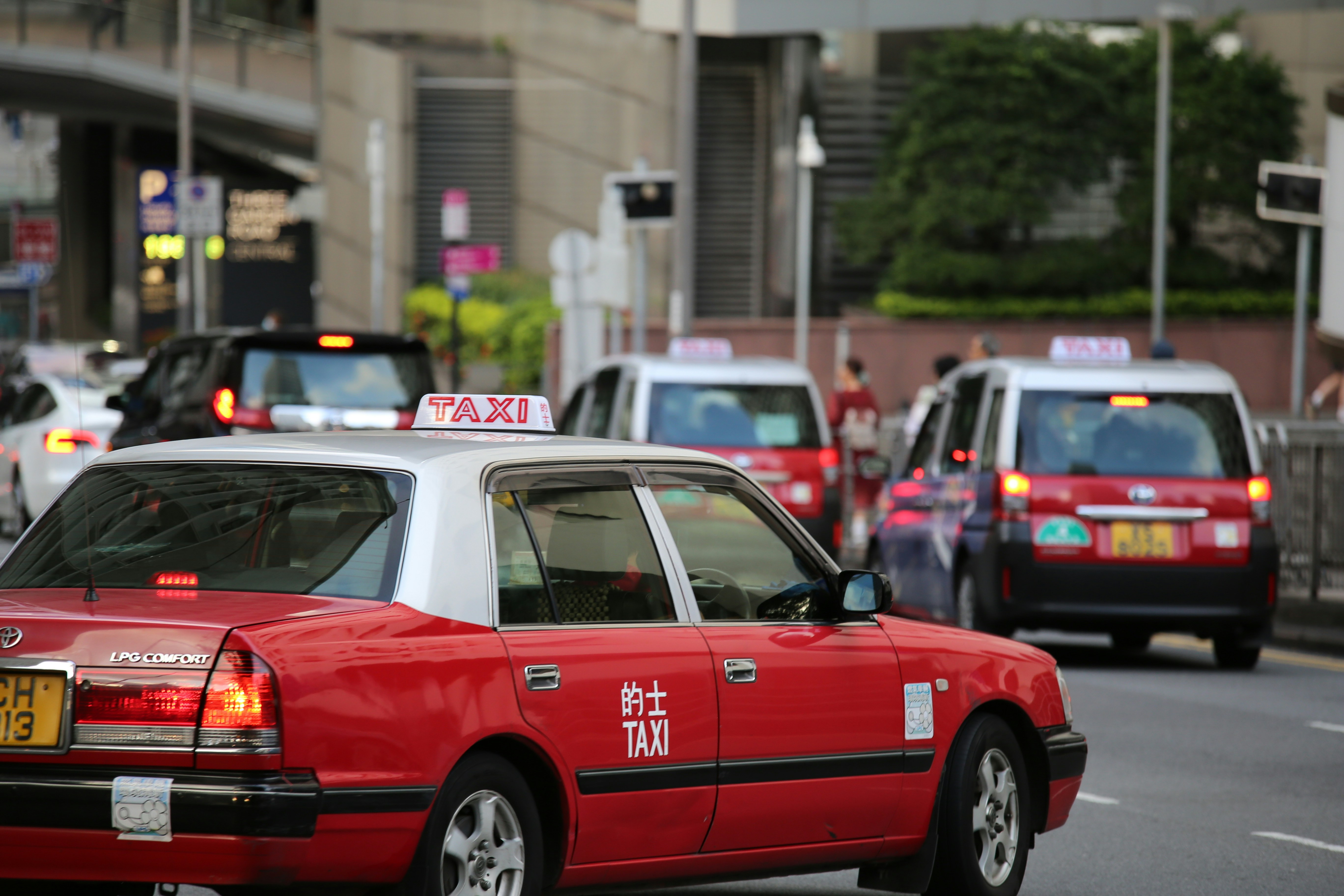 A red taxi cab driving down a street next to tall buildings photo ...