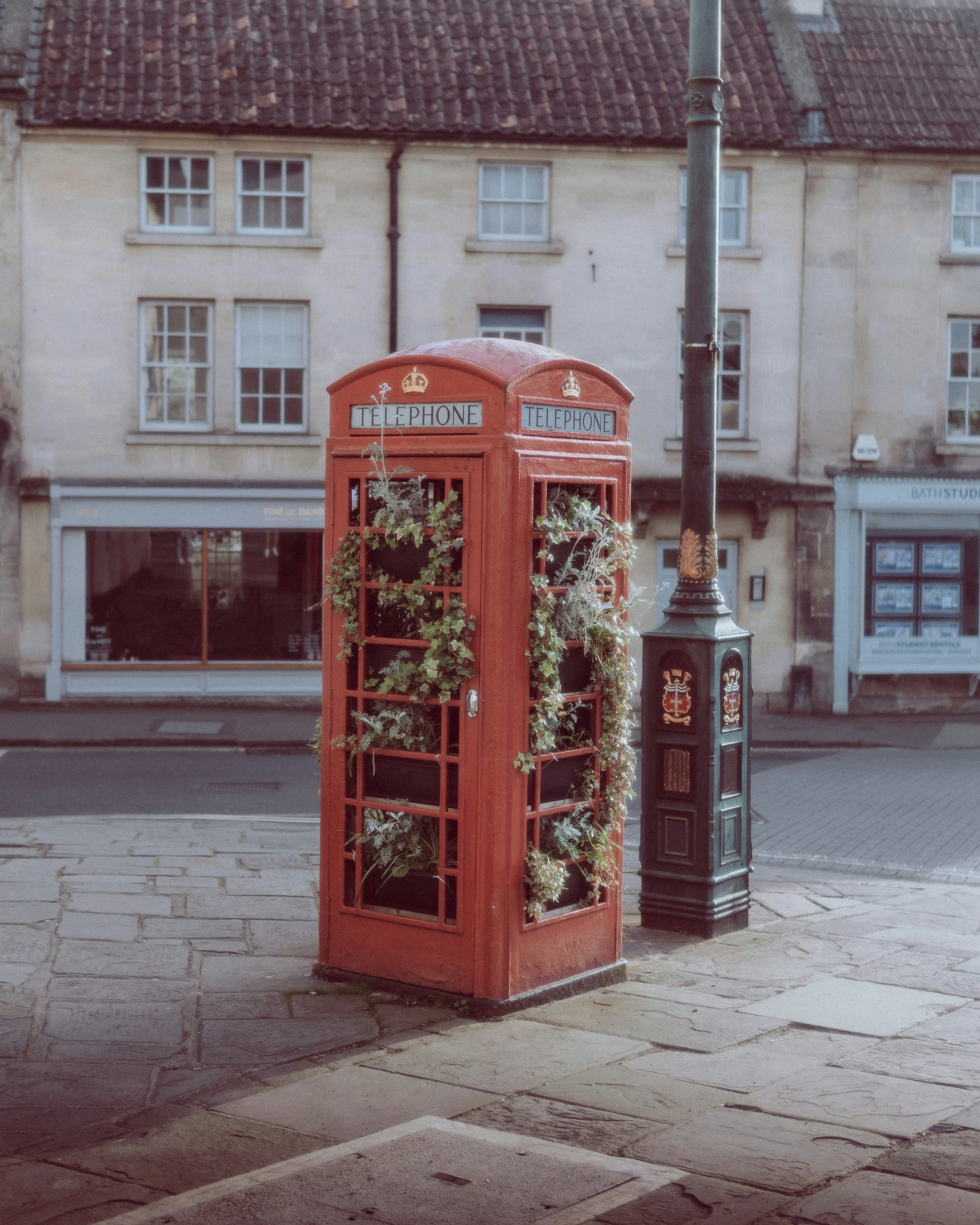 A red phone booth sitting on the side of a street photo – Free Phone ...