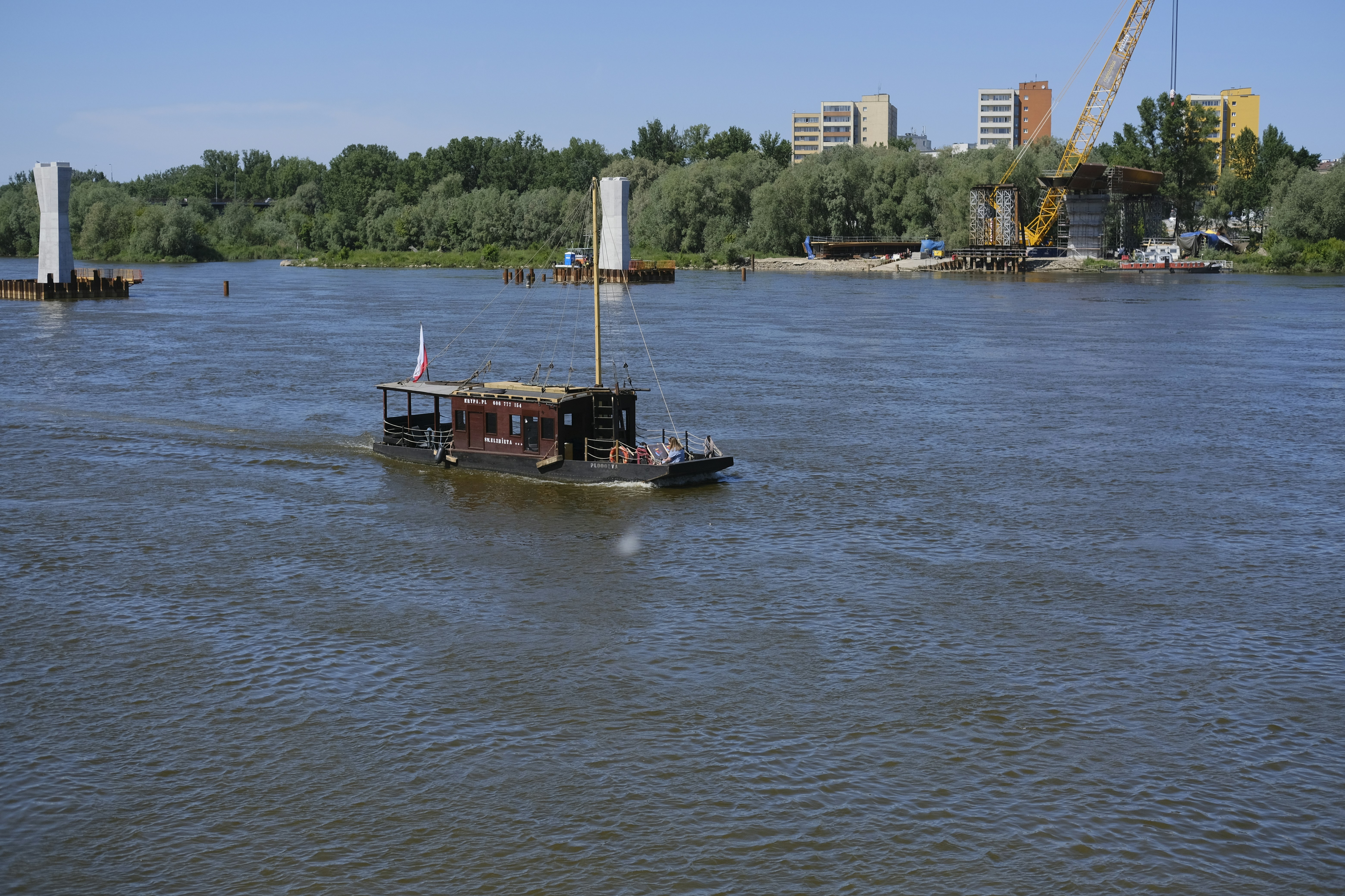 Houseboat Drift on a Wide River Amid Urban Growth