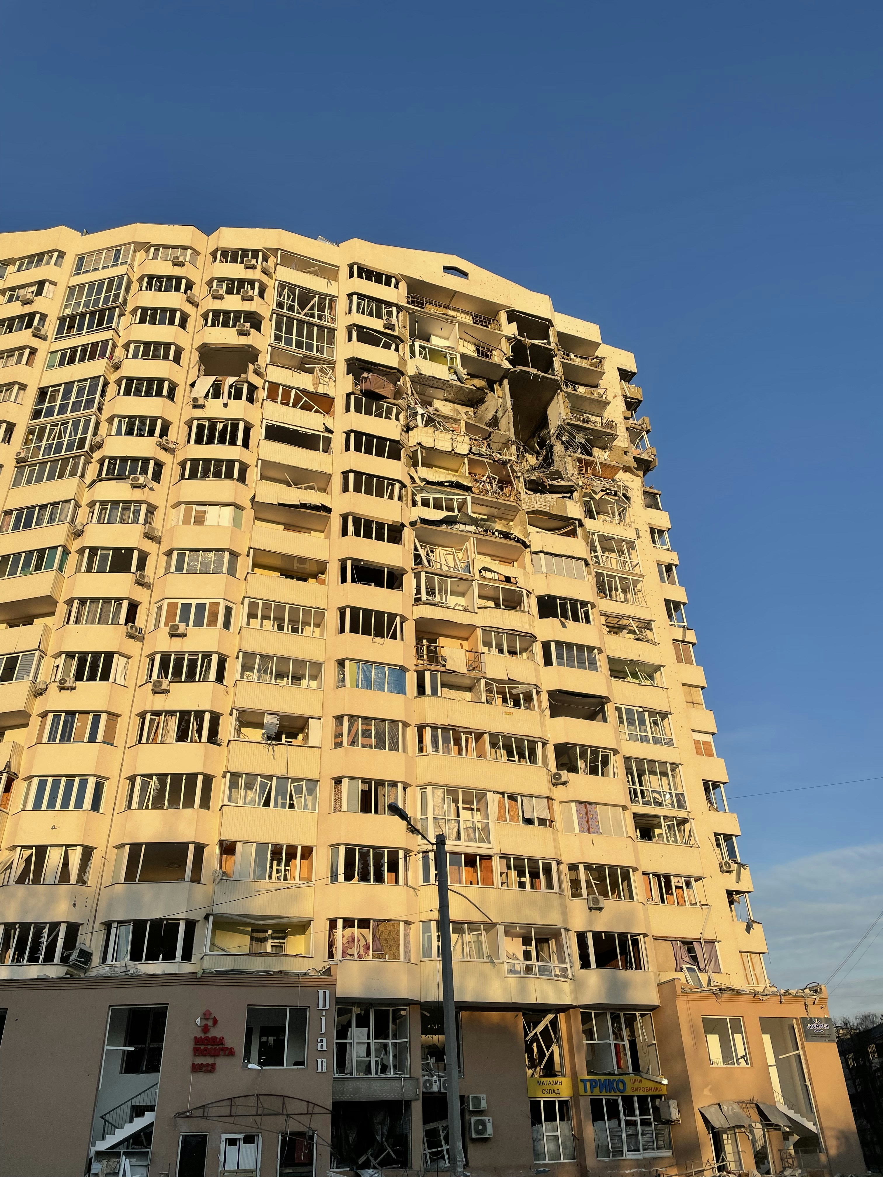 Sunlit high-rise with a damaged facade under a clear blue sky