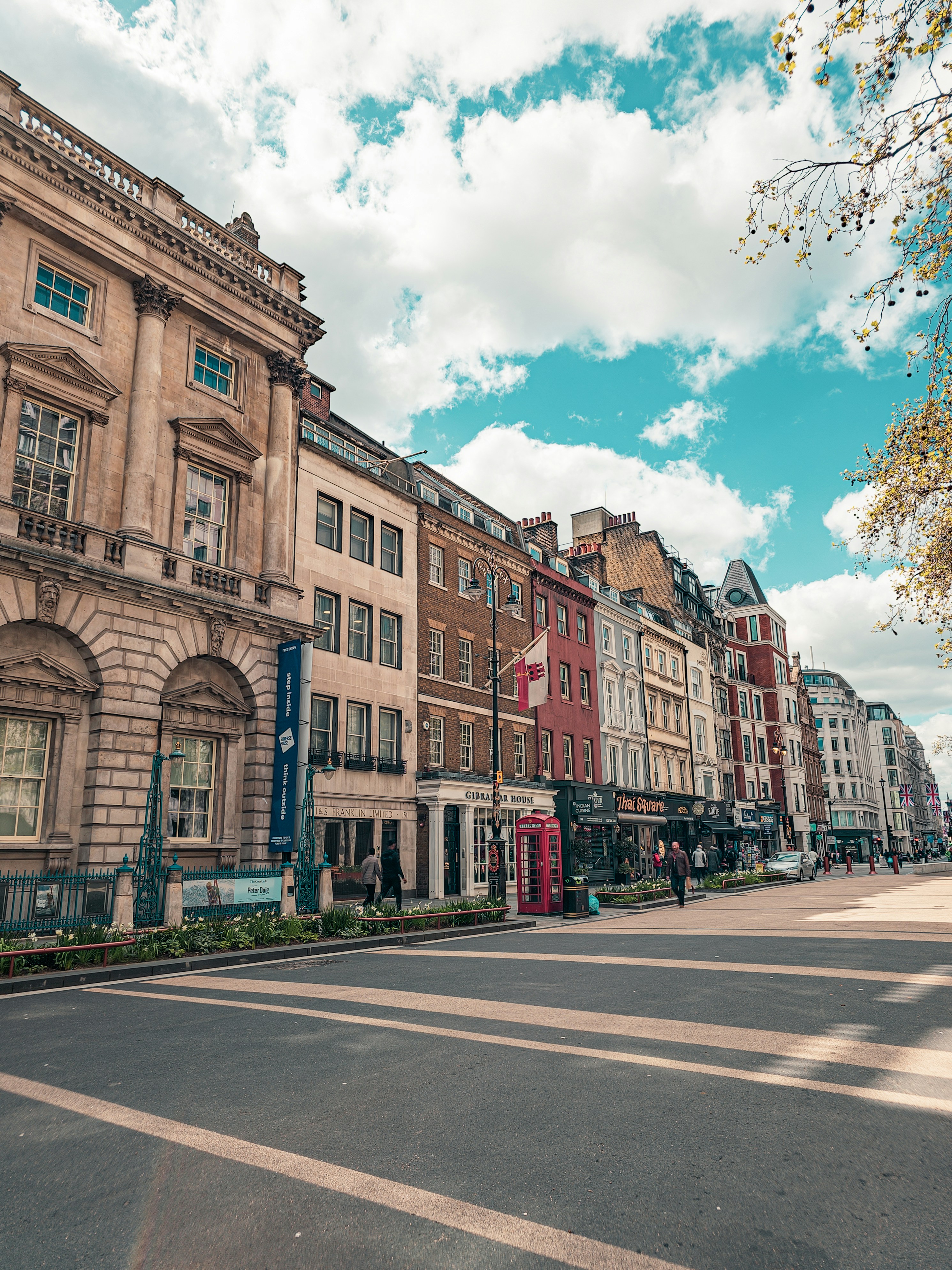 Charming street view featuring a blend of historic and modern architecture under a vibrant blue sky. A classic red telephone booth adds a touch of nostalgia.